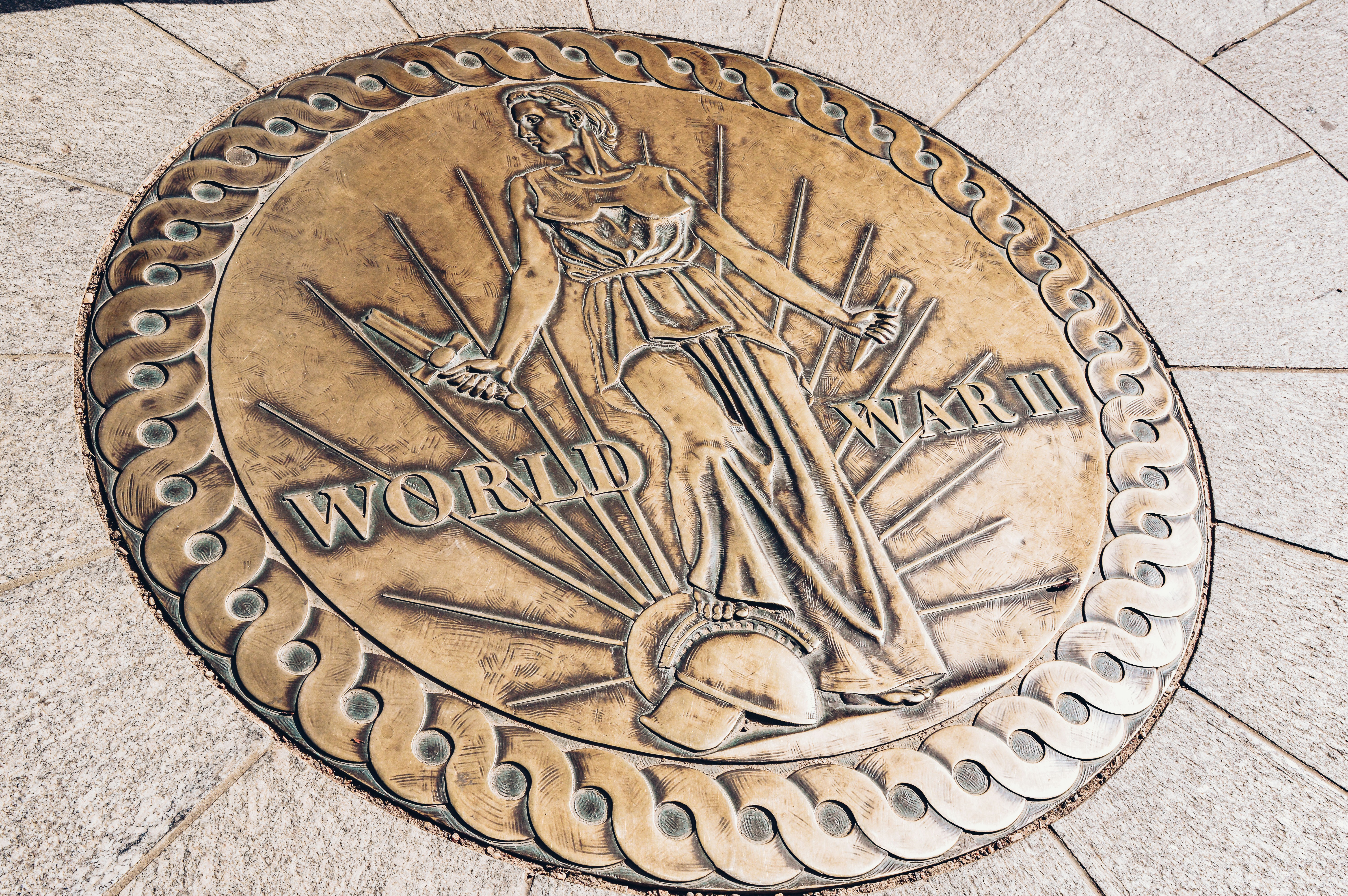 Bronze World War II Memorial Lid: Radiant Emblem on a City Plaza