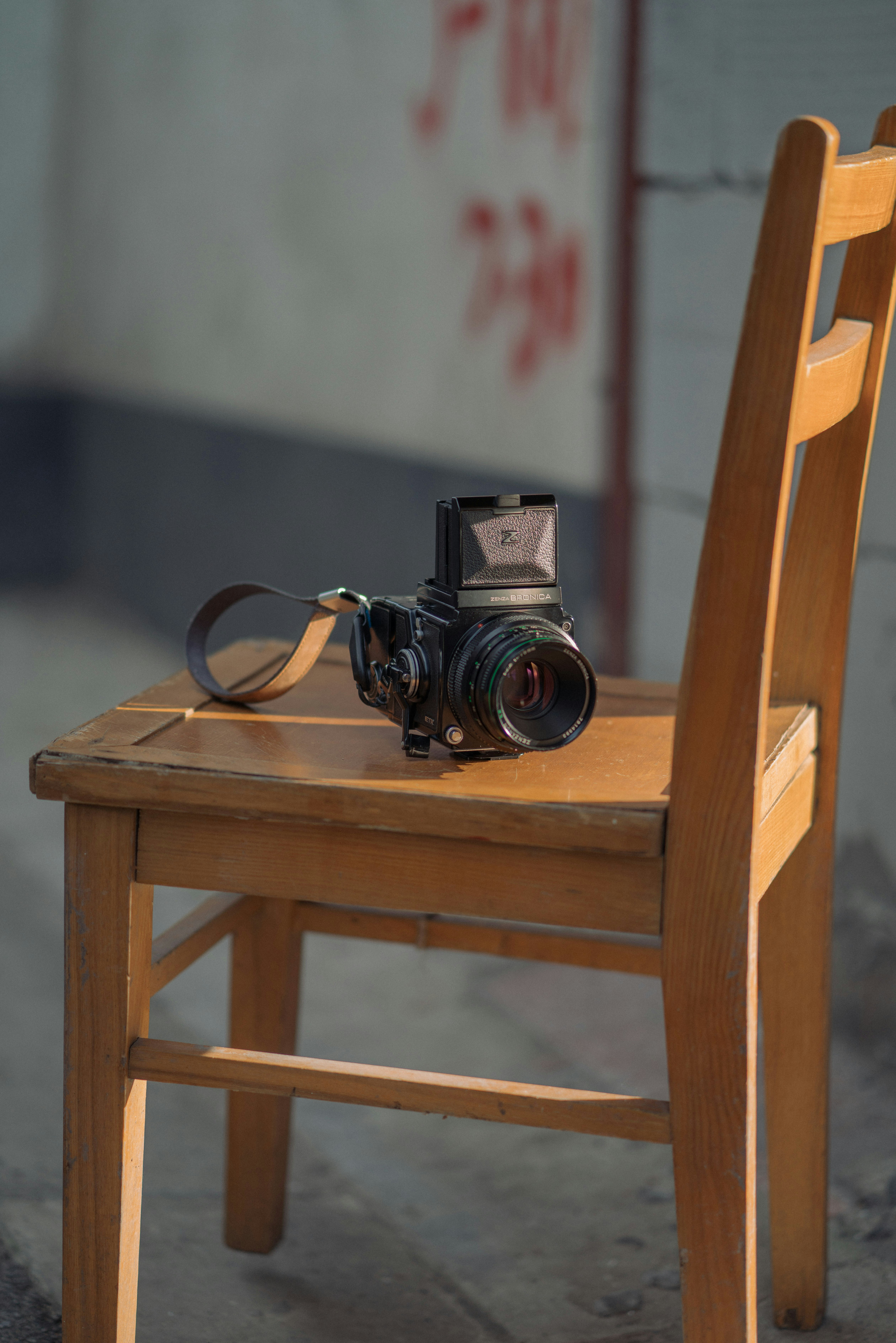 A camera sitting on top of a wooden chair photo – Free Camera Image on ...