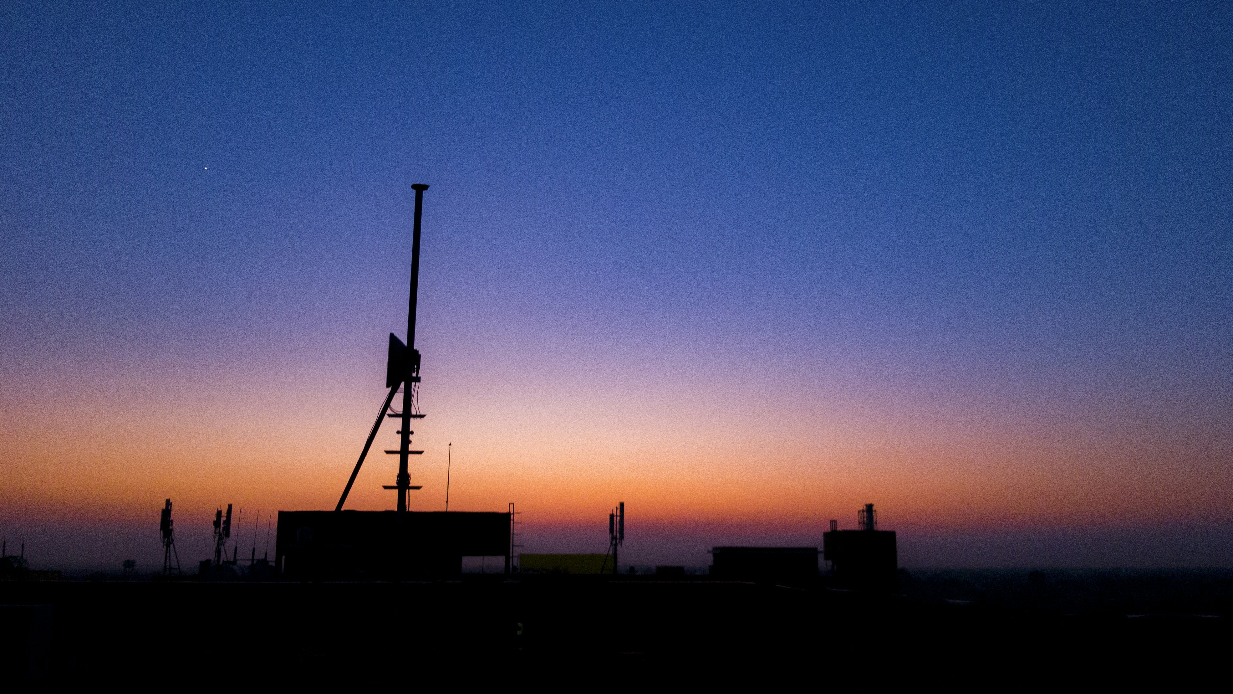 The sun is setting over a building with a radio antenna photo – Free ...