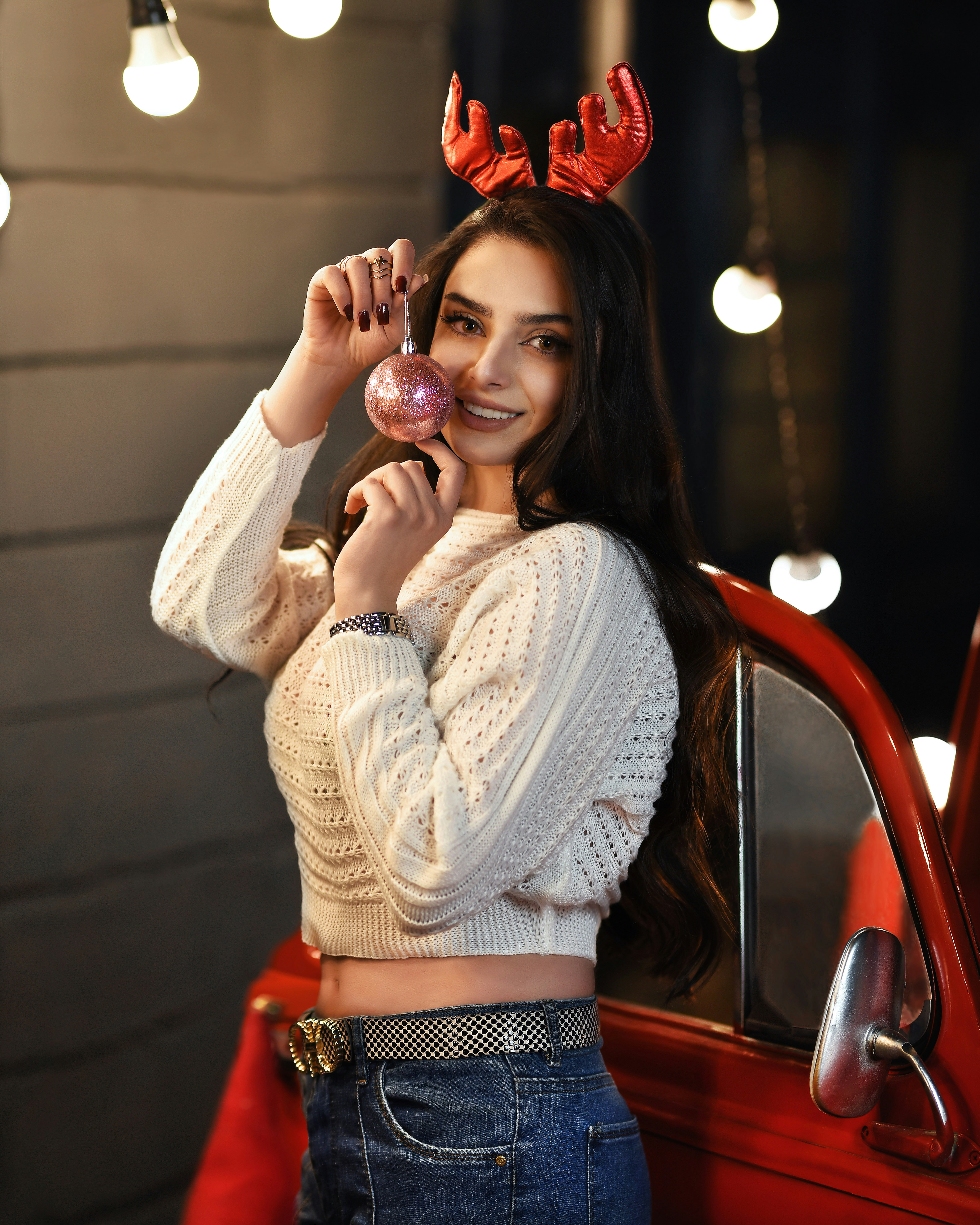 Ornament and Warmth: Festive Portrait by a Vintage Red Car