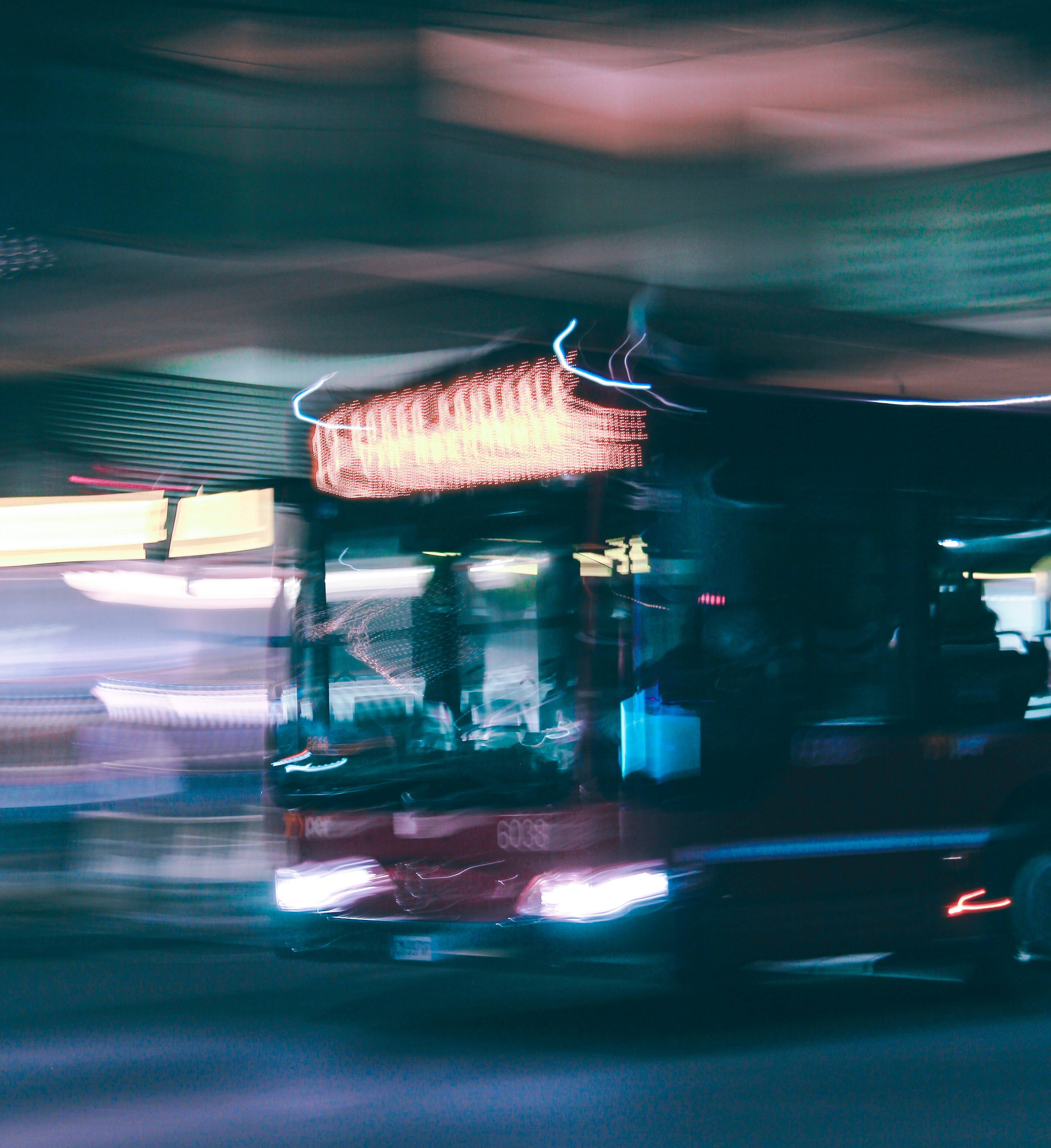 A red bus driving down a street at night photo – Free Bus Image on Unsplash