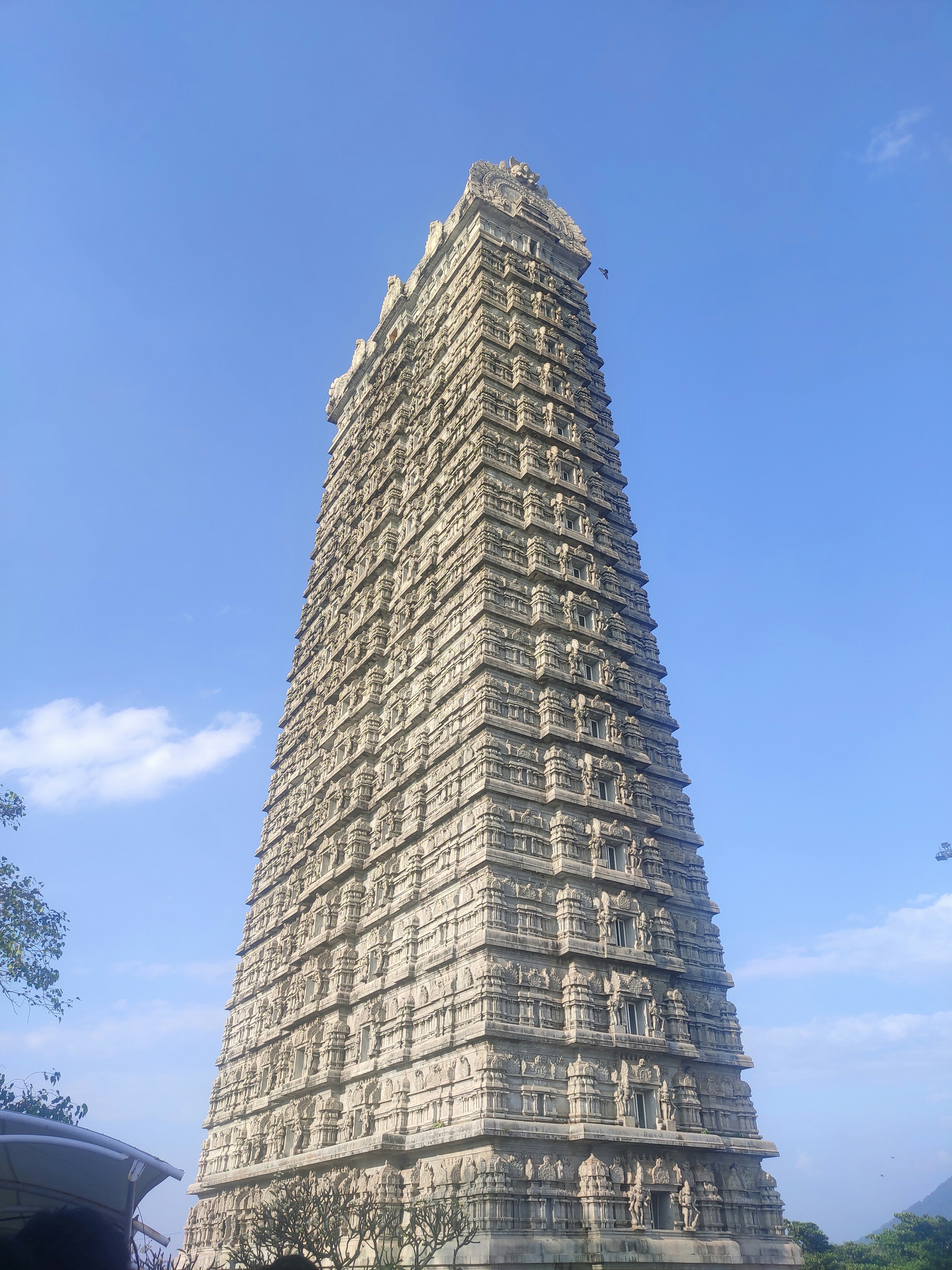 Intricately carved temple tower reaching for the sky against a clear blue backdrop.