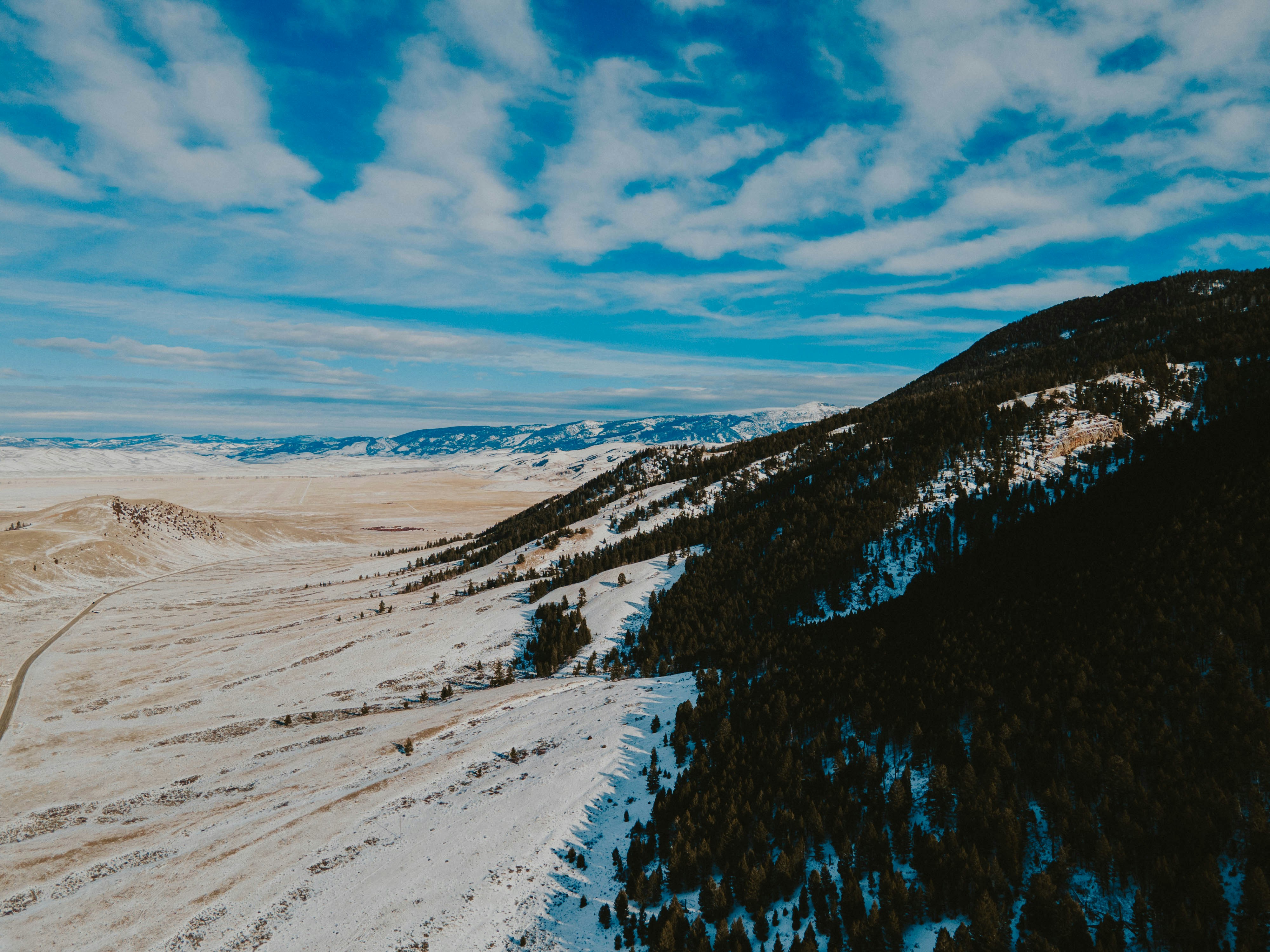 Snow-covered mountain slopes with a vast sky and scattered clouds overhead.