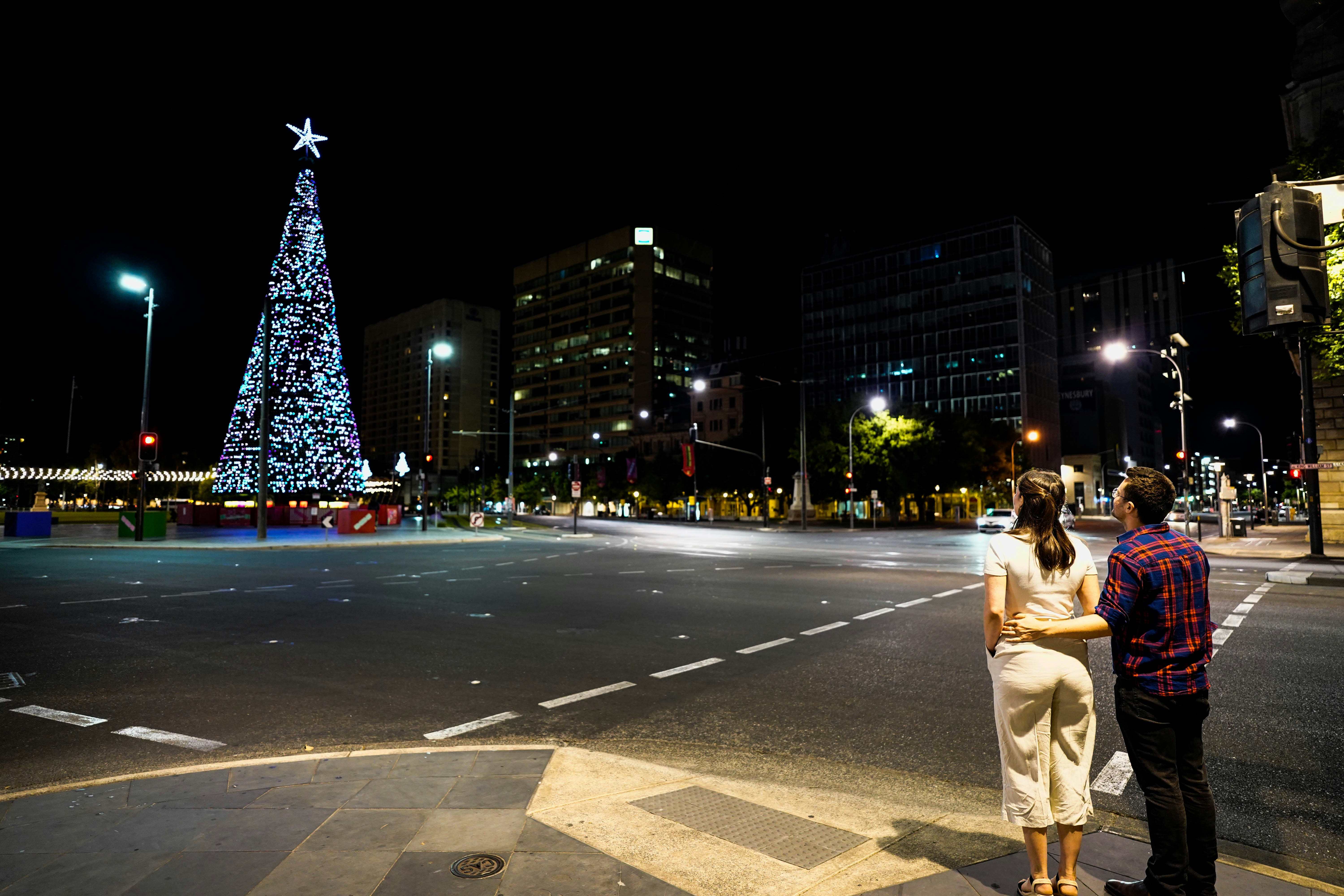 Couple under City Lights by a Festive Tree