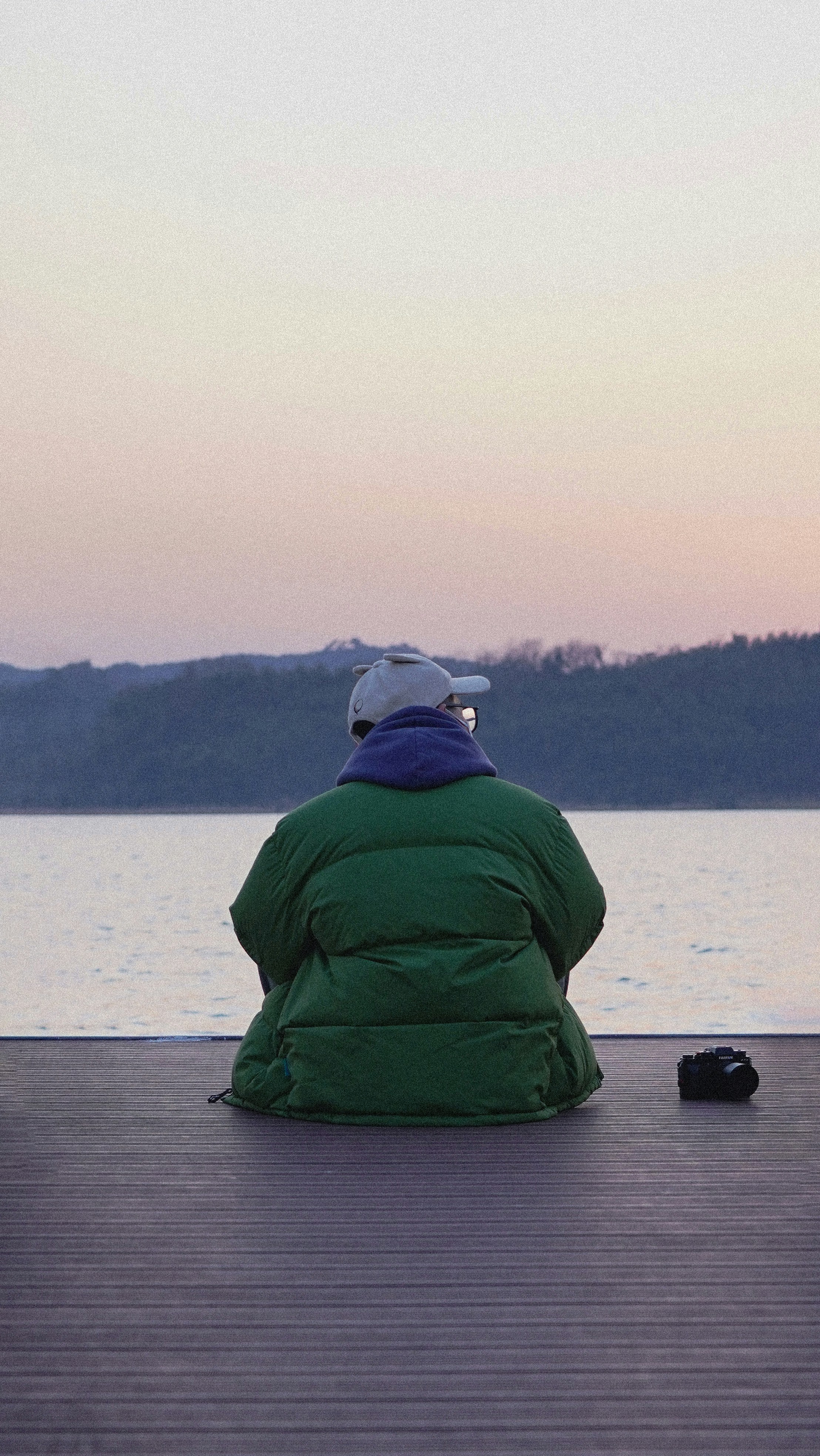 A person sitting on a dock looking out at the water photo – Free Human ...