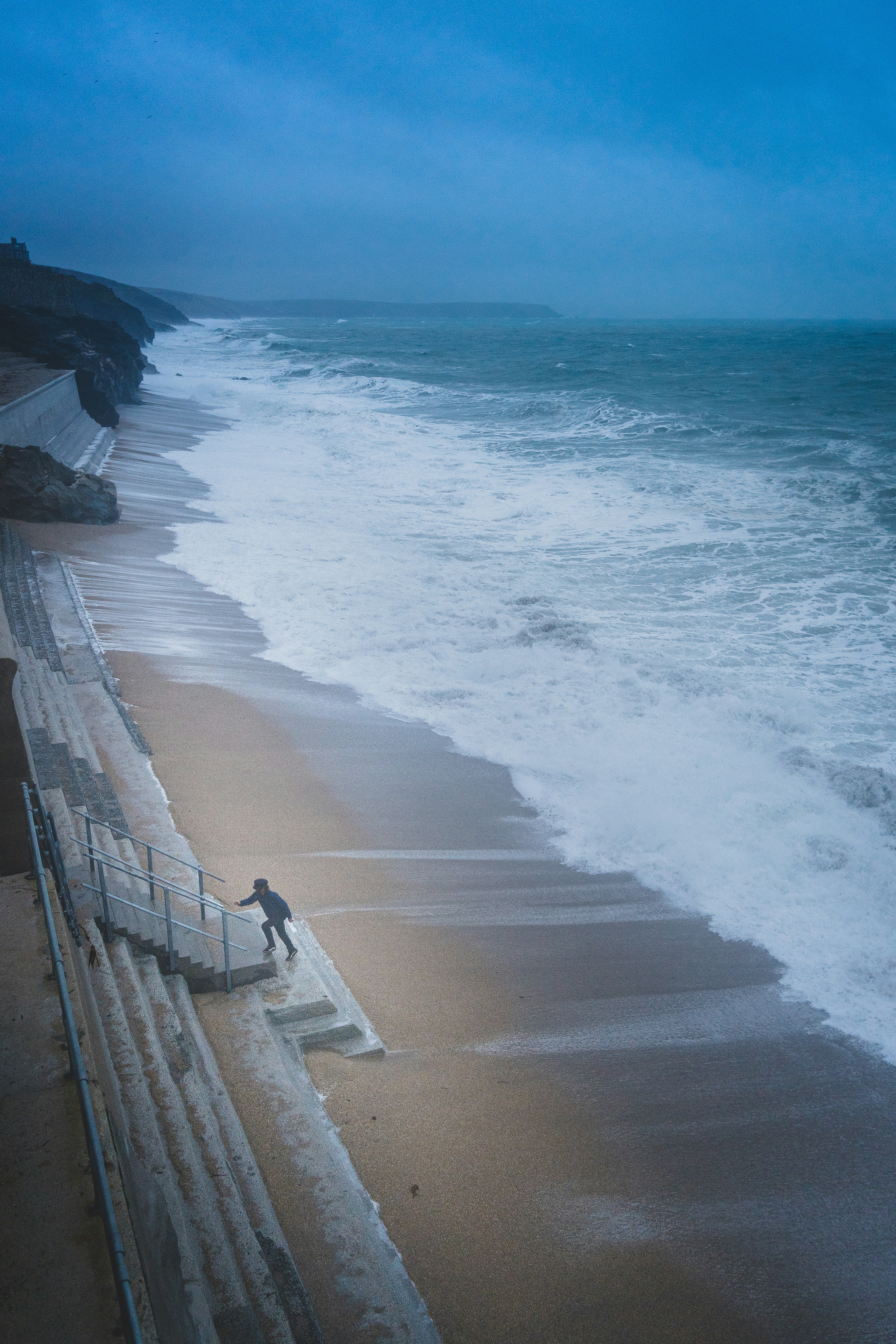 Stride Along the Sloped Seawall: A Lone Figure Against a Brimming Tide