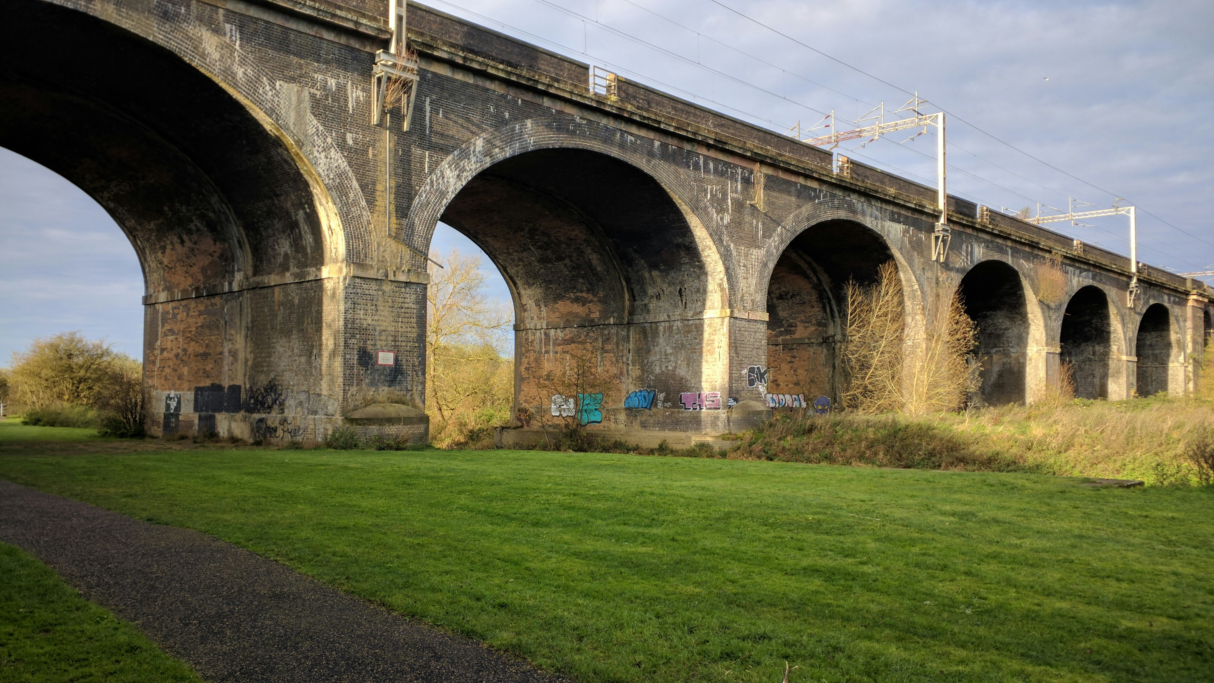 A train bridge over a lush green field photo – Free Rail bridge Image ...