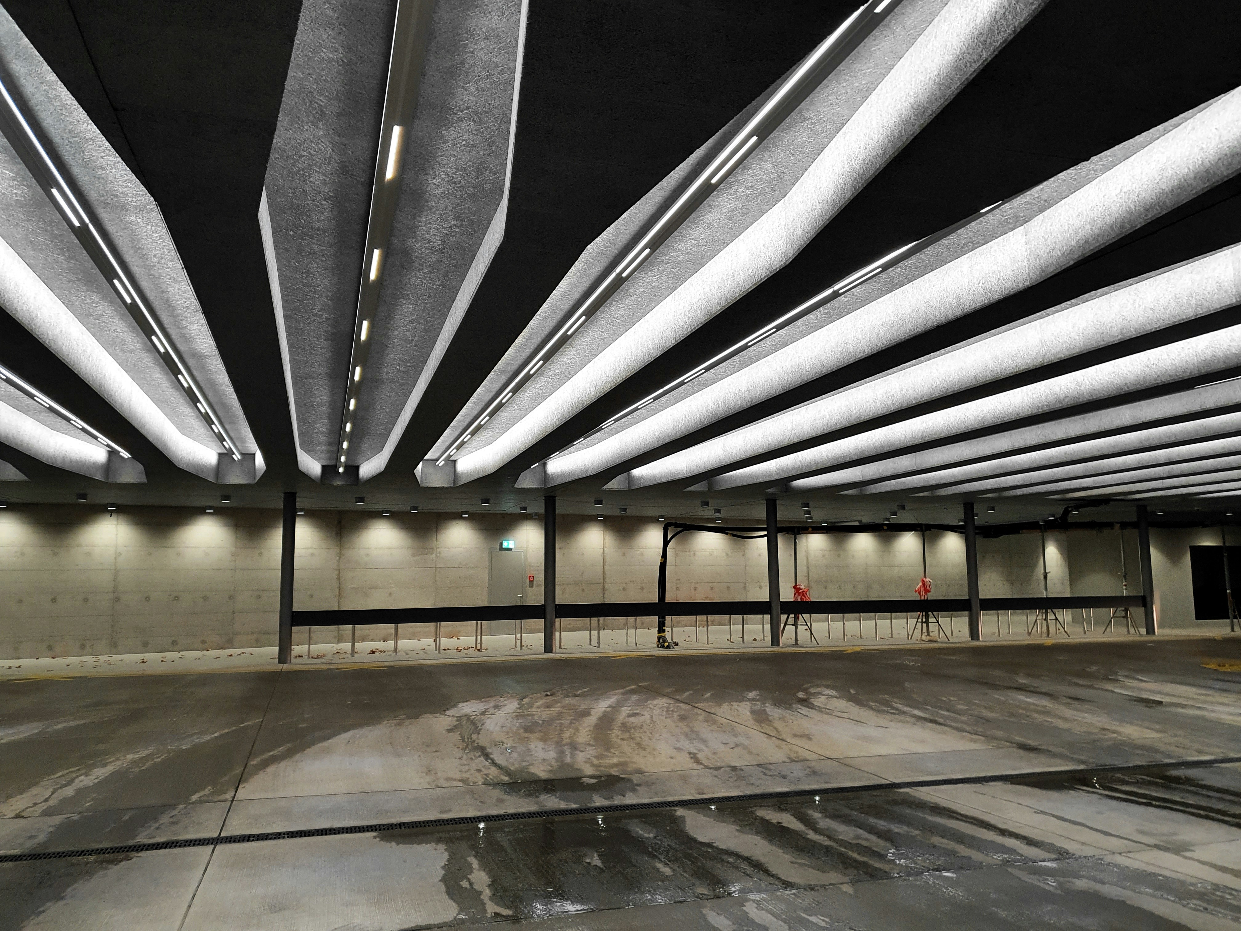 Architectural interior showcasing linear light fixtures and polished concrete flooring in an expansive area.