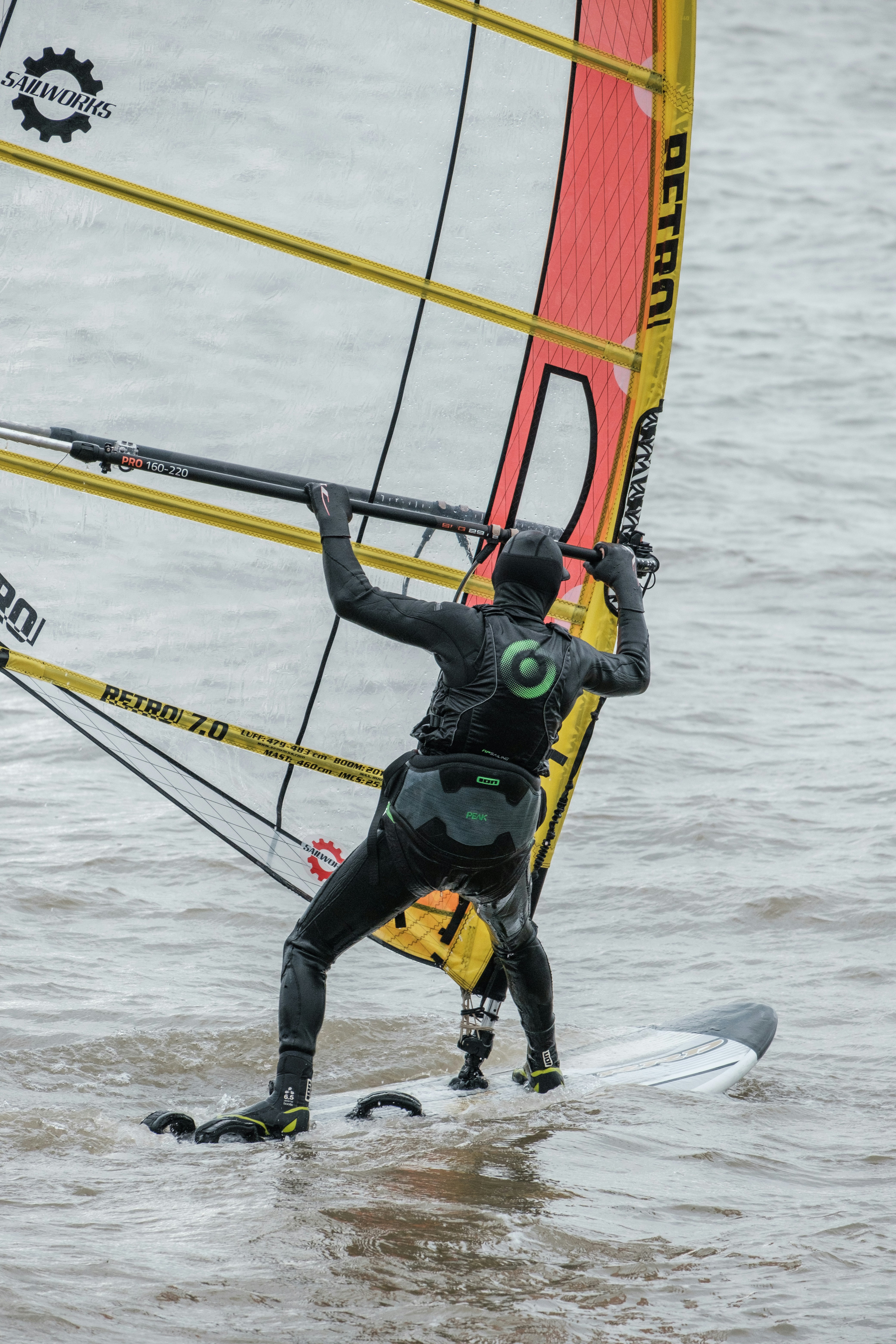 A man riding a wind sail on top of a body of water photo – Free ...