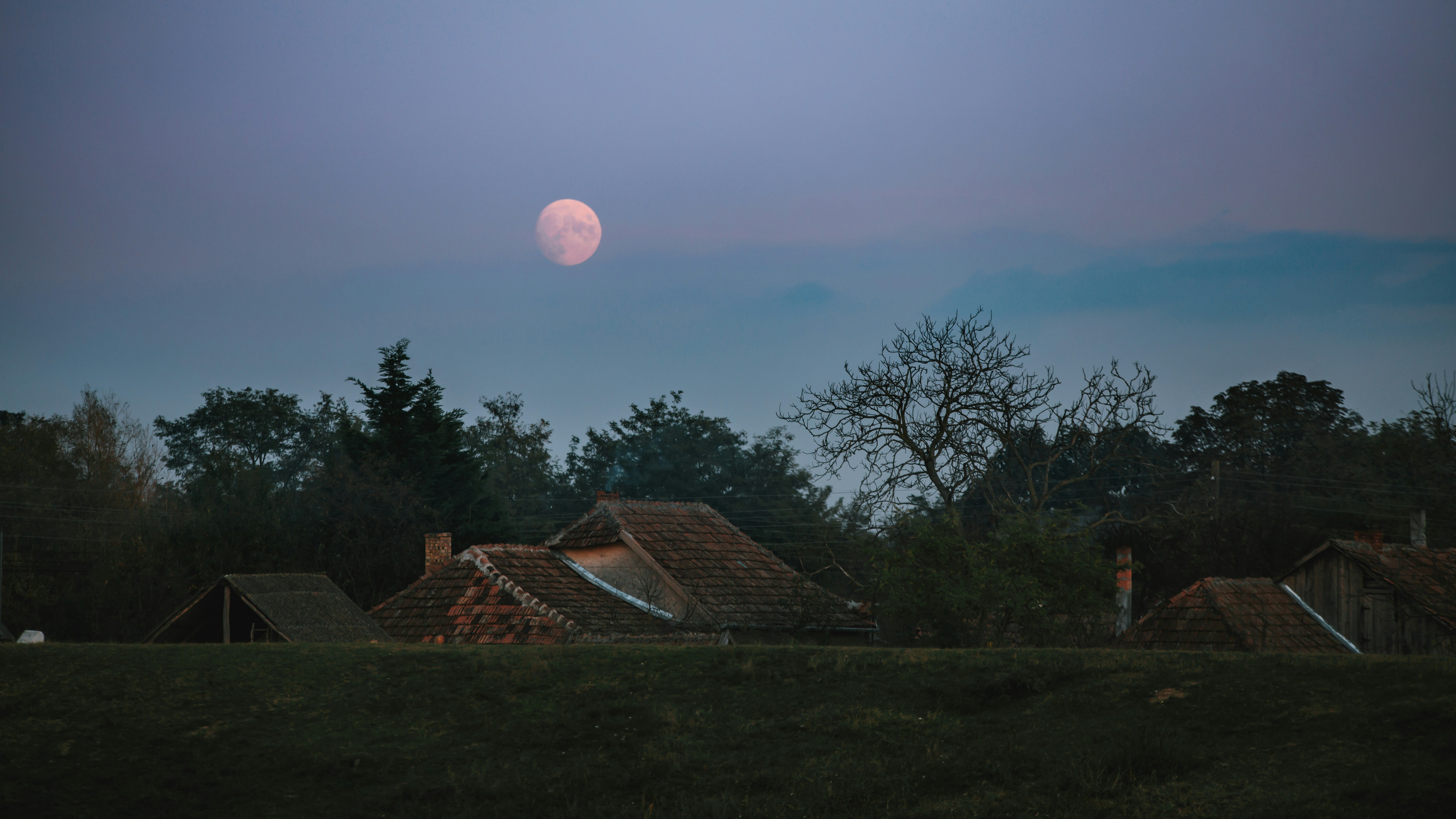 Moonrise over a Quiet Village: Pale Moon Above Red-Tiled Rooftops at Blue Hour