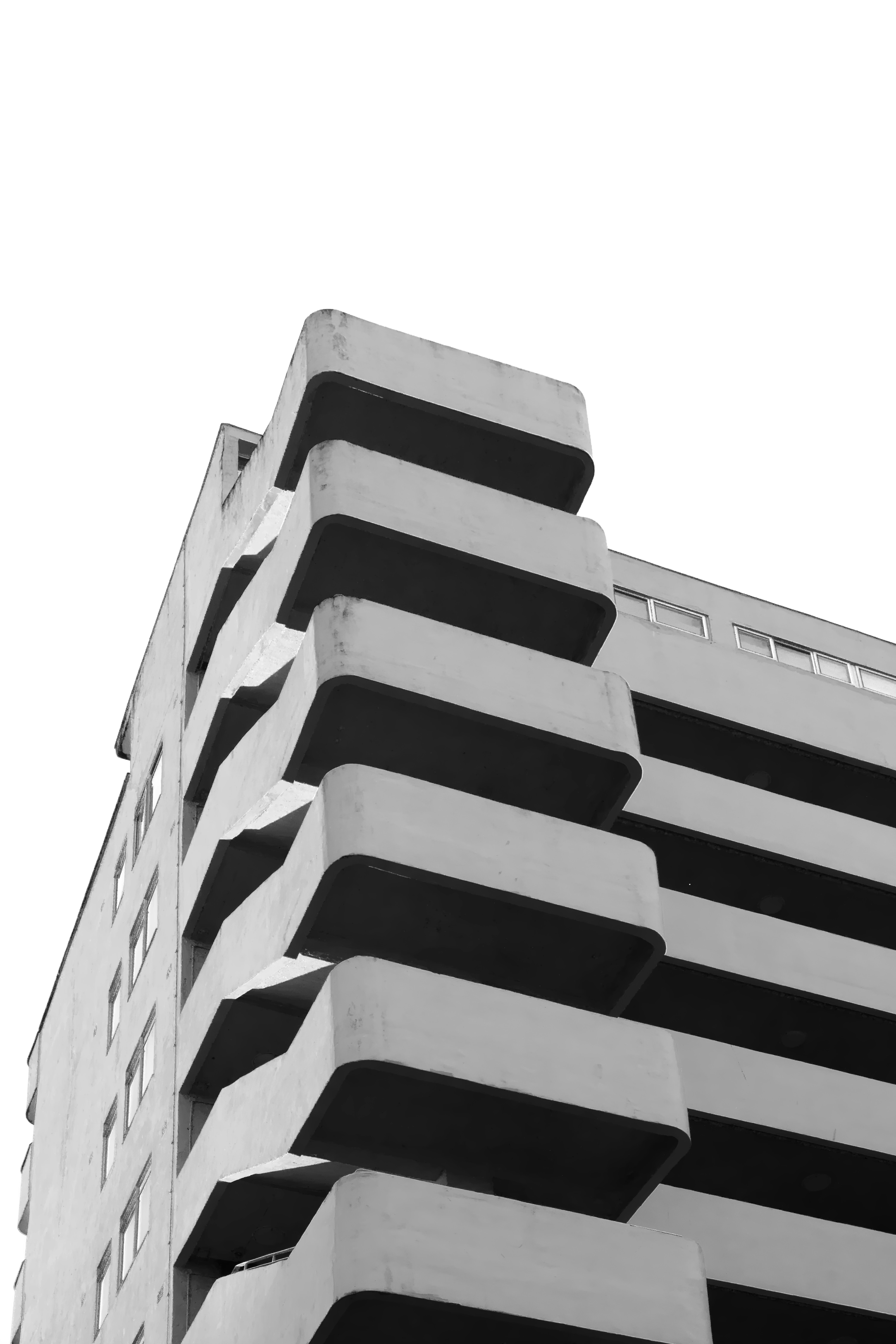 Abstract view of a modern building showcasing distinctive curved balconies against a stark white background.