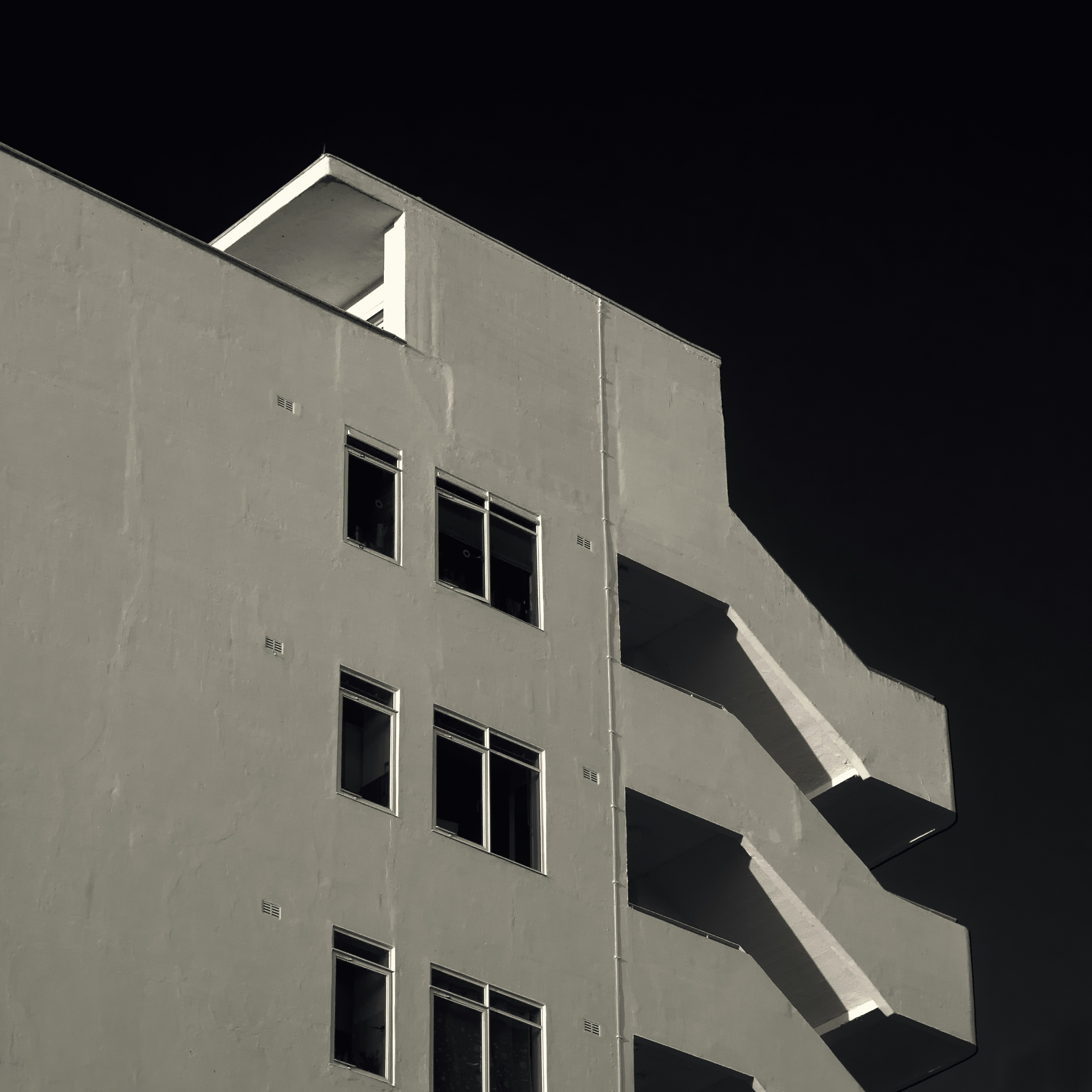 Abstract architectural structure with sharp lines and contrasting shadows, highlighting the interplay of light and geometry.