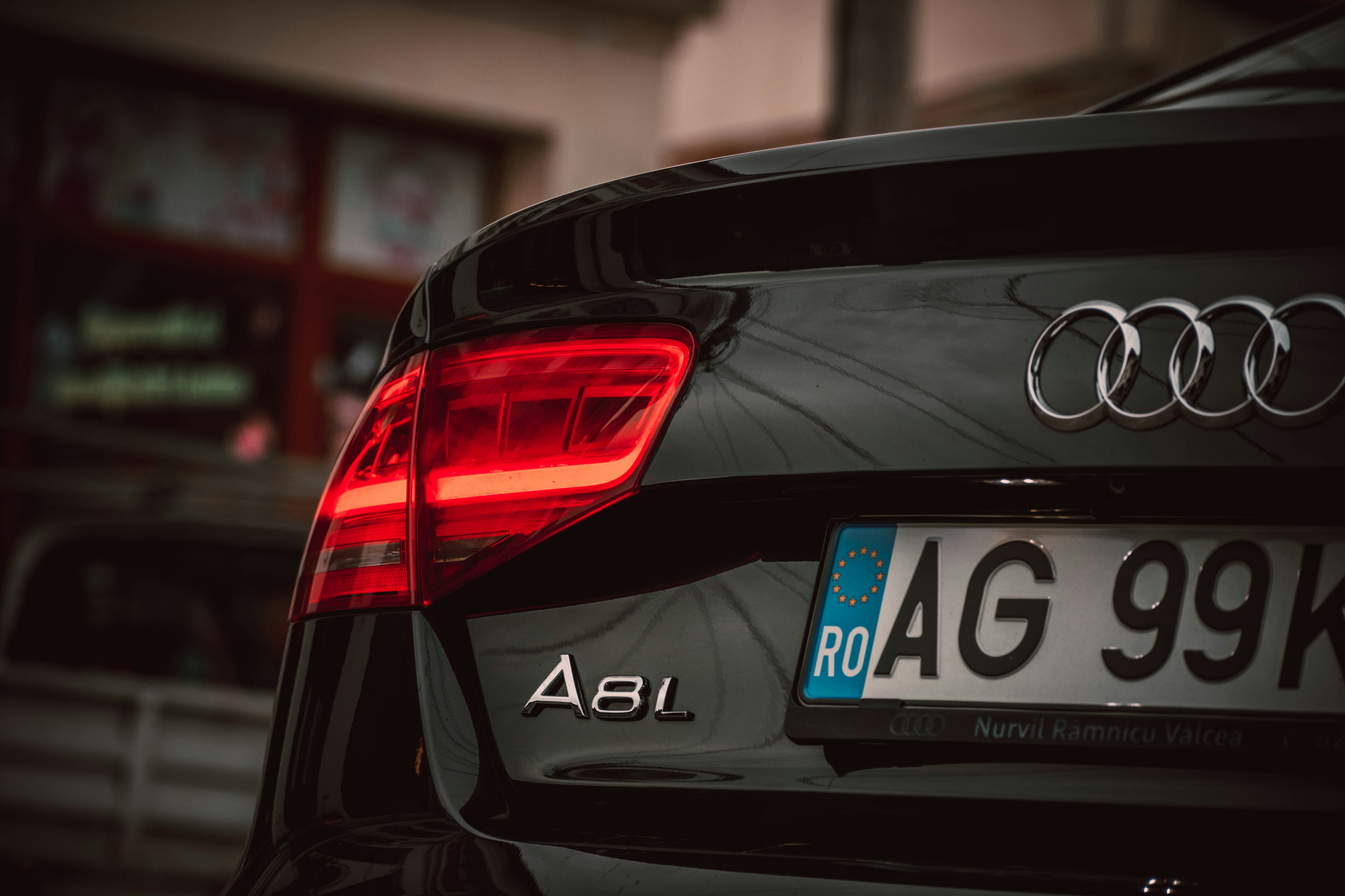 Close-up of a black Audi A8 with illuminated taillights and a visible license plate in an urban setting.