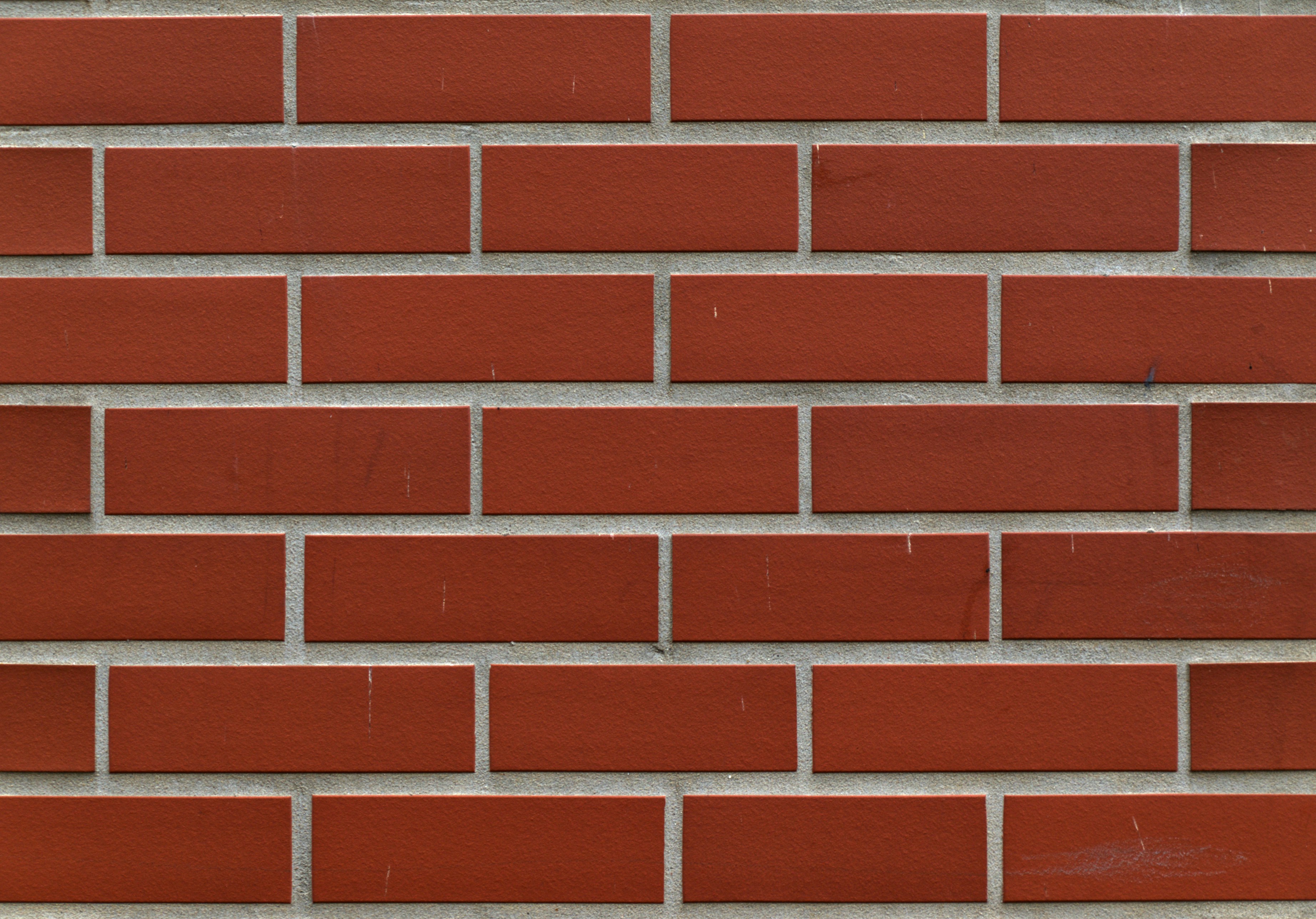 A close-up view of a brick wall featuring a repetitive pattern of reddish-brown bricks and light gray mortar. The arrangement highlights the texture and uniformity of the construction material.