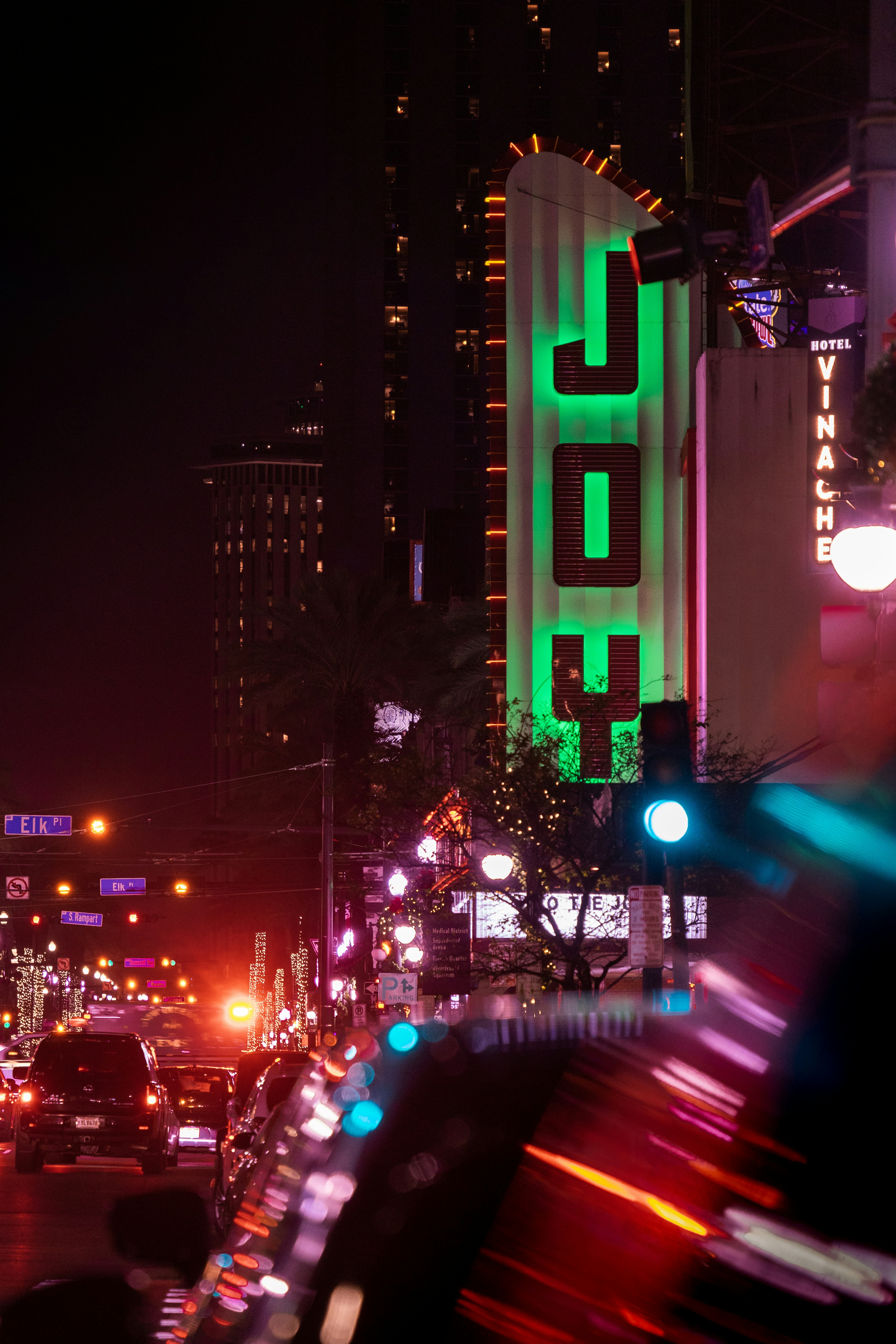 Emerald Neon JOY Sign Looms Over a Night-Glazed Downtown Street