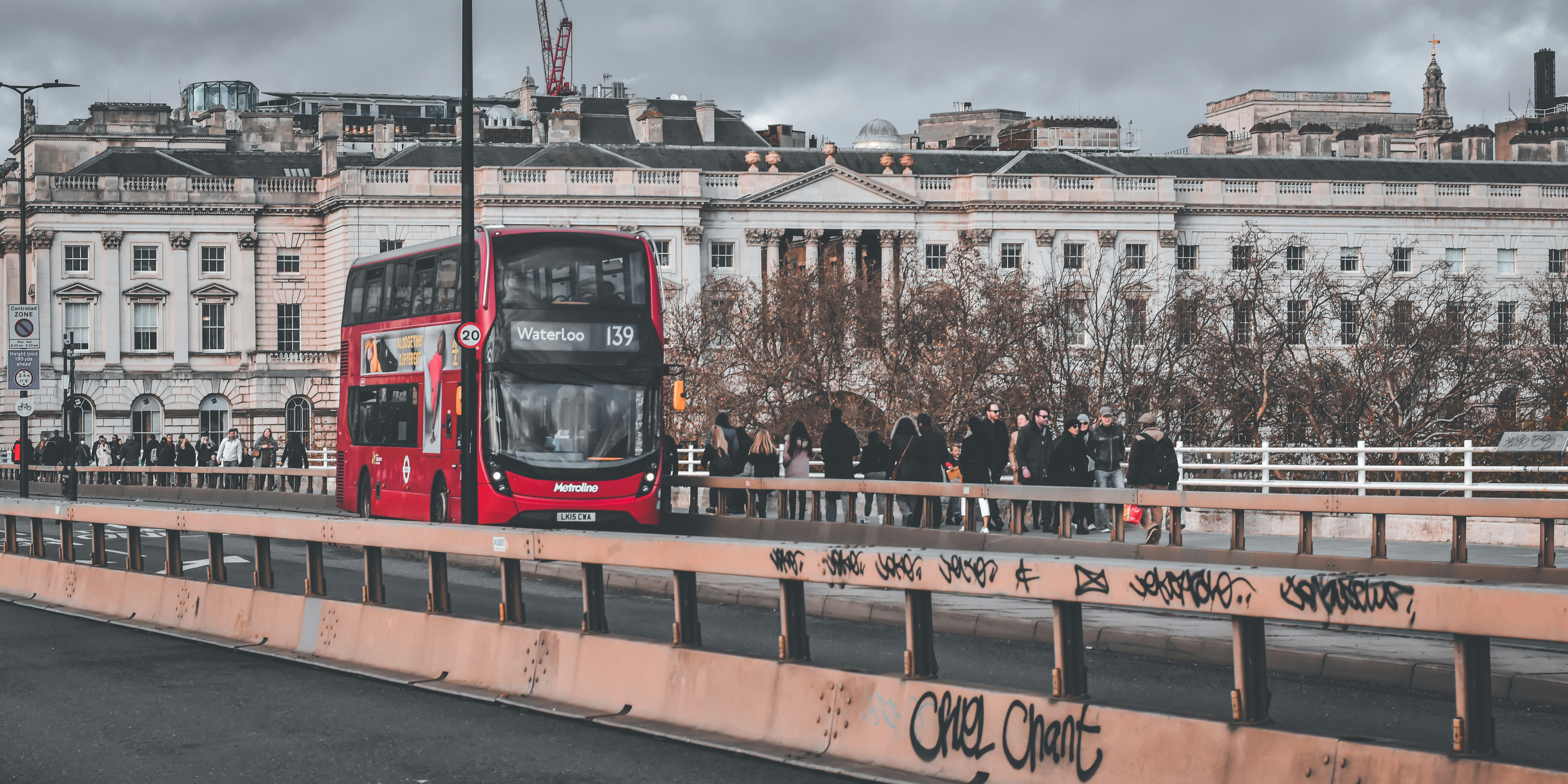 A red double decker bus driving over a bridge photo – Free London Image ...