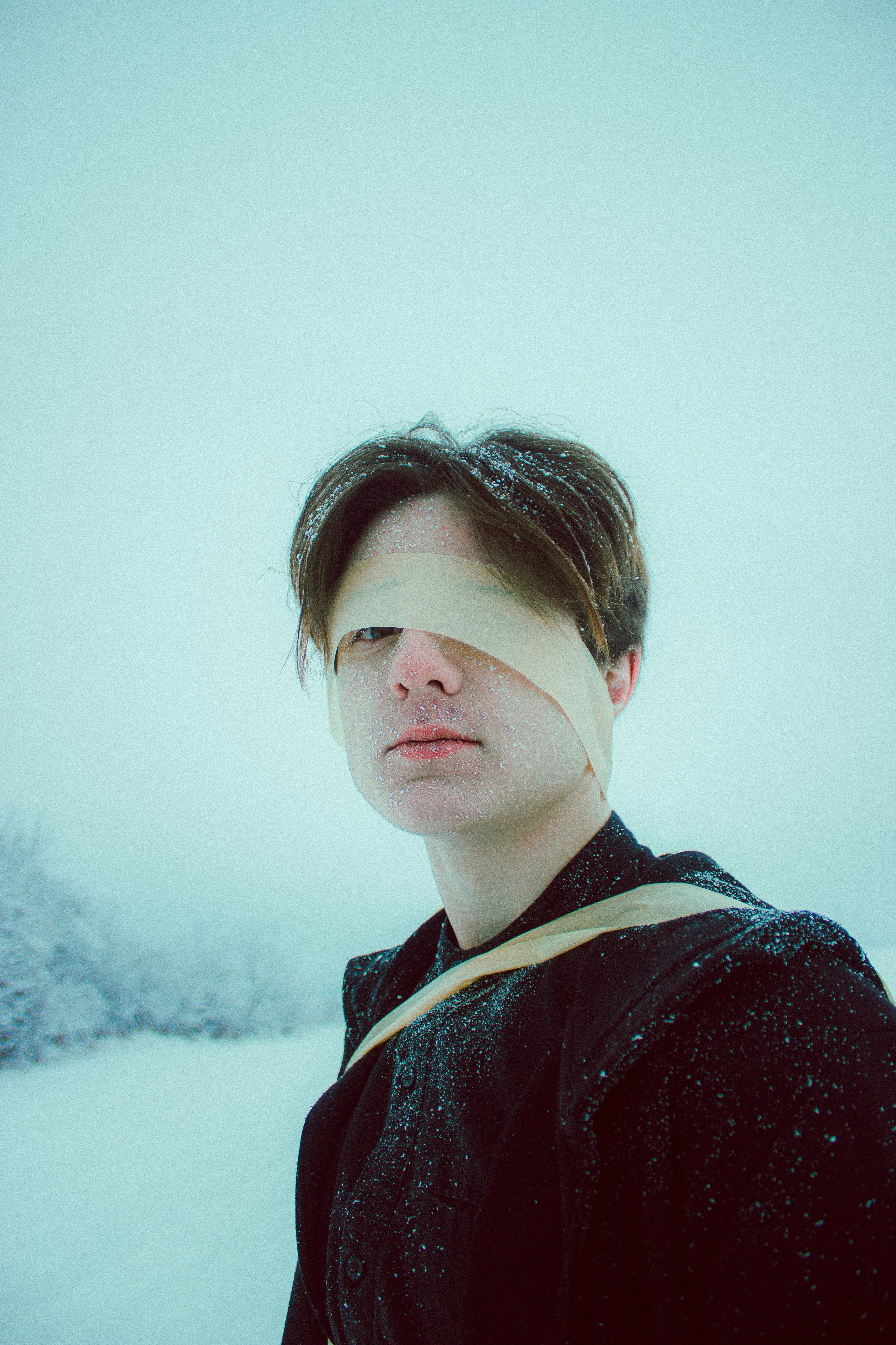 Winter Veil Portrait: A Face Wrapped in Beige Bandage Amid Snow