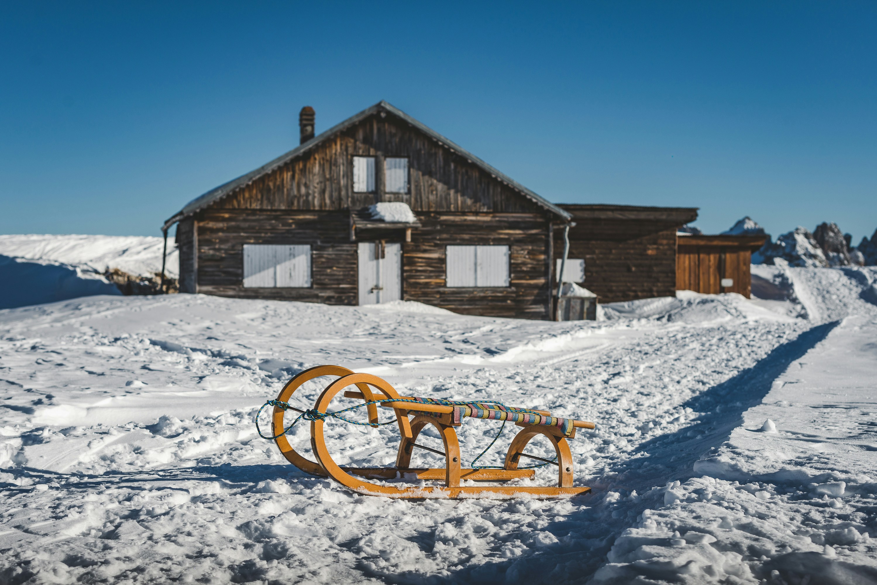 A sled is laying in the snow in front of a house photo – Free Winter ...