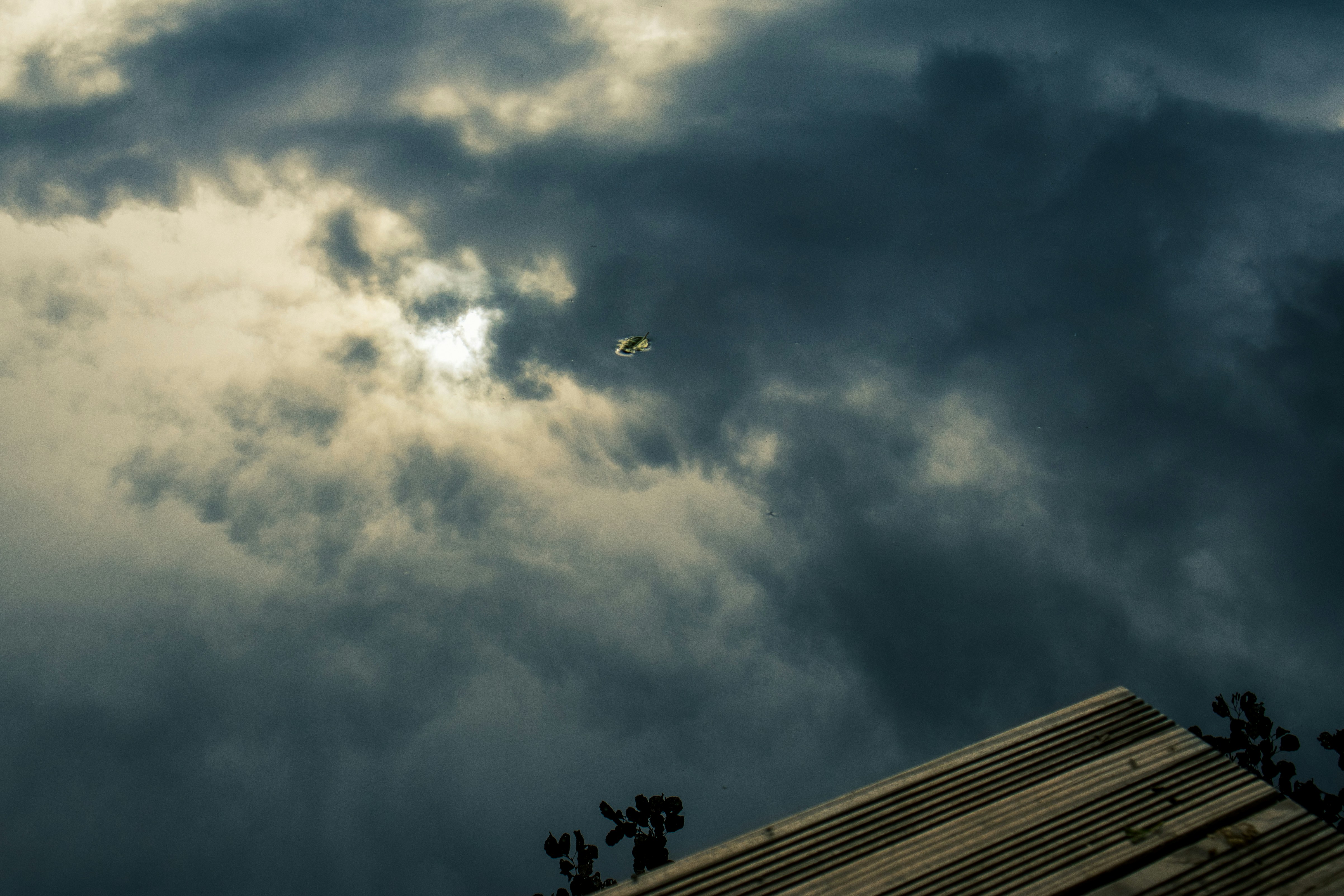 Narrow Sunbreak Over Corrugated Rooftop Beneath a Turbulent Sky