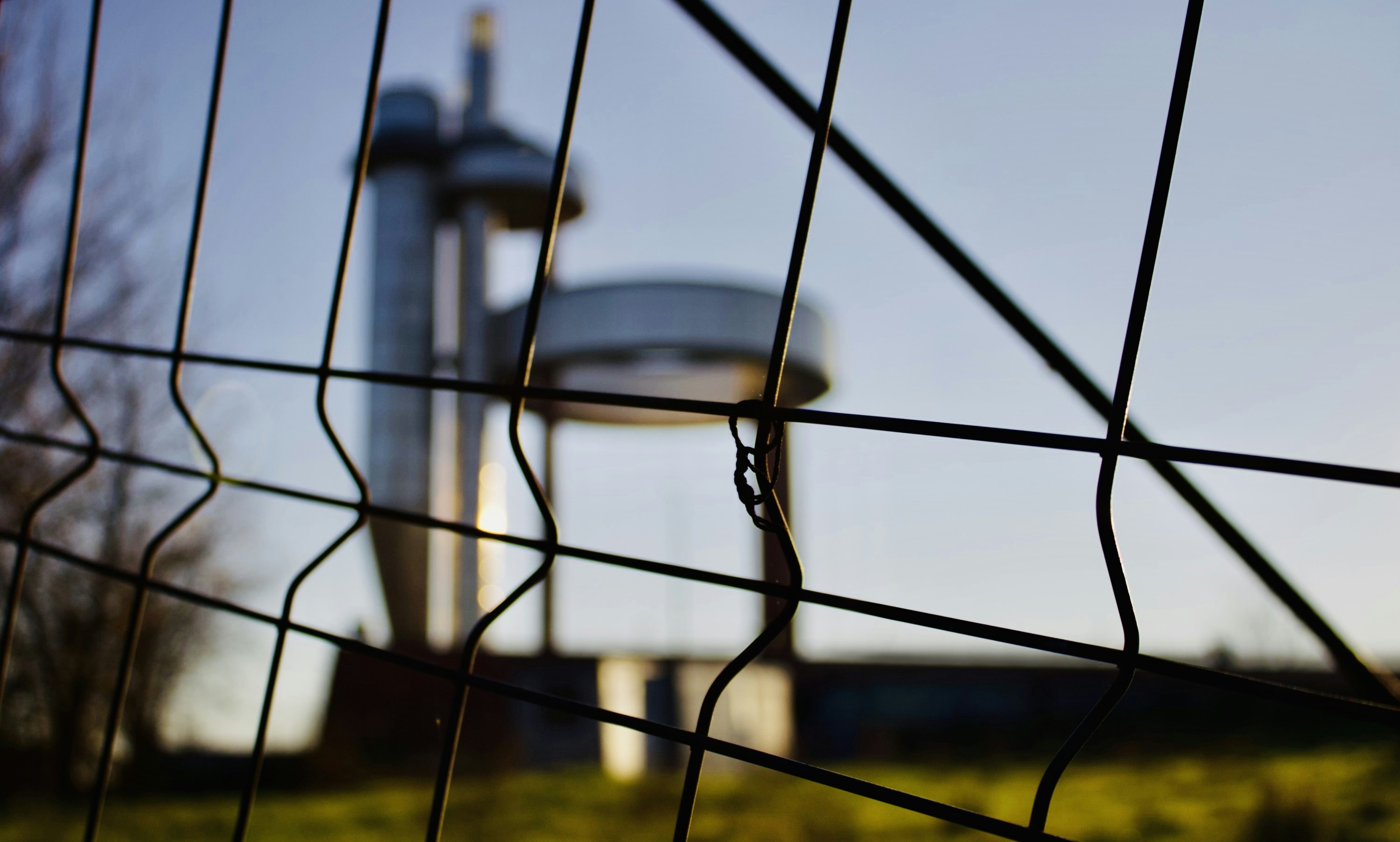 Crisscrossed Barrier: Field Gate Framing a Distant Tower