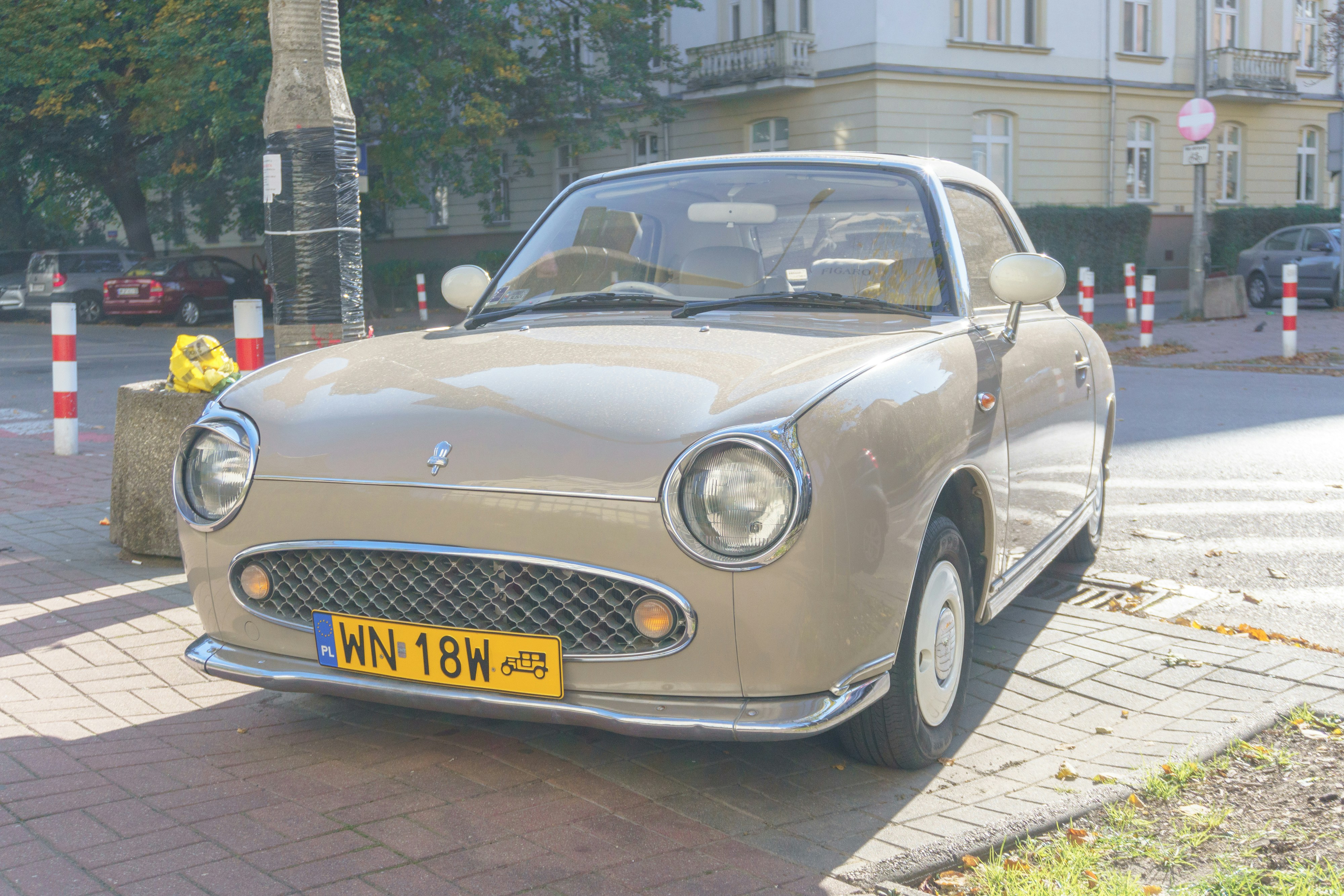 Beige Vintage Coupe on a Sunlit European Cobblestone Street