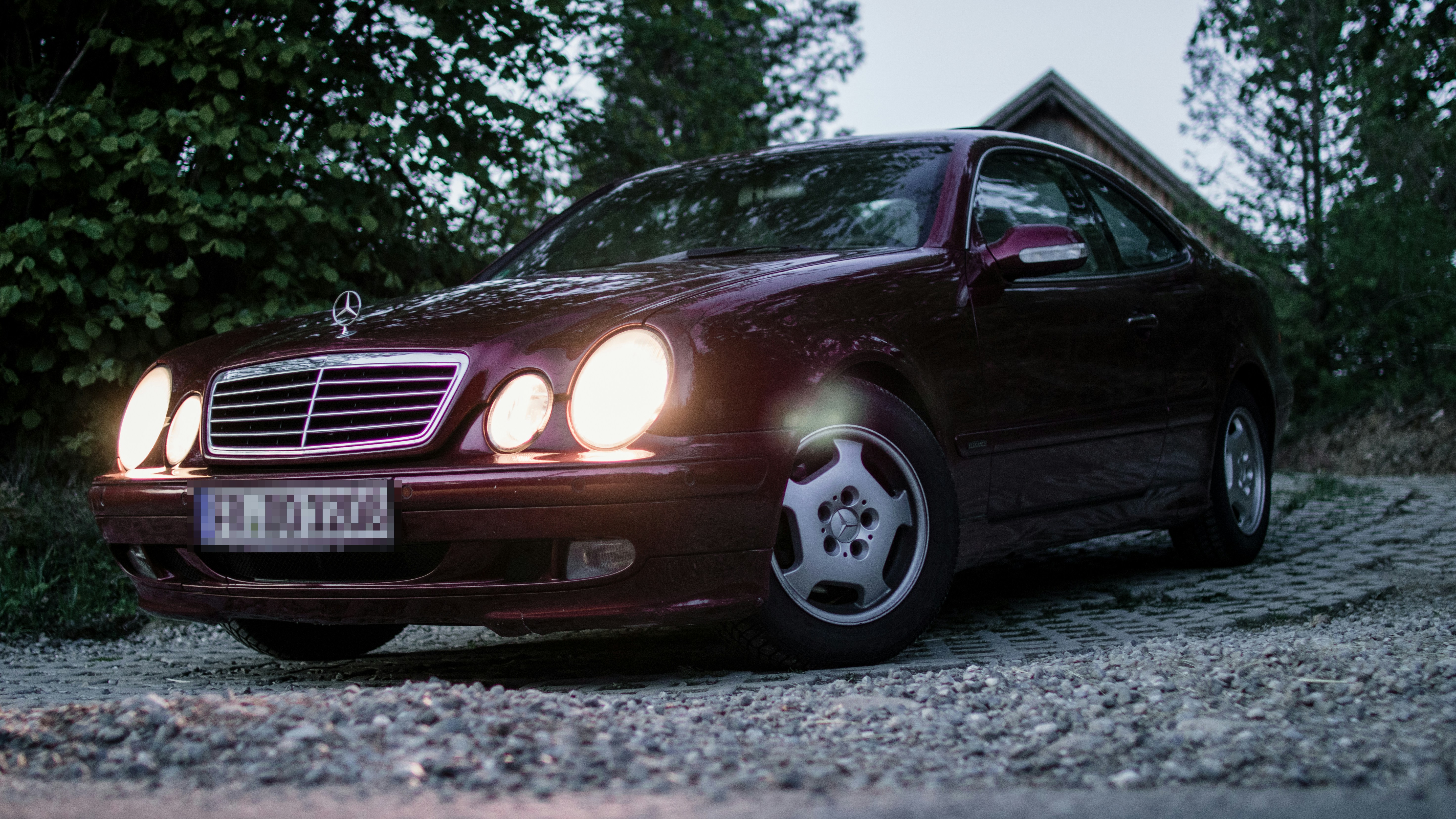 Crimson Mercedes on Gravel at Dusk: Headlights Alight
