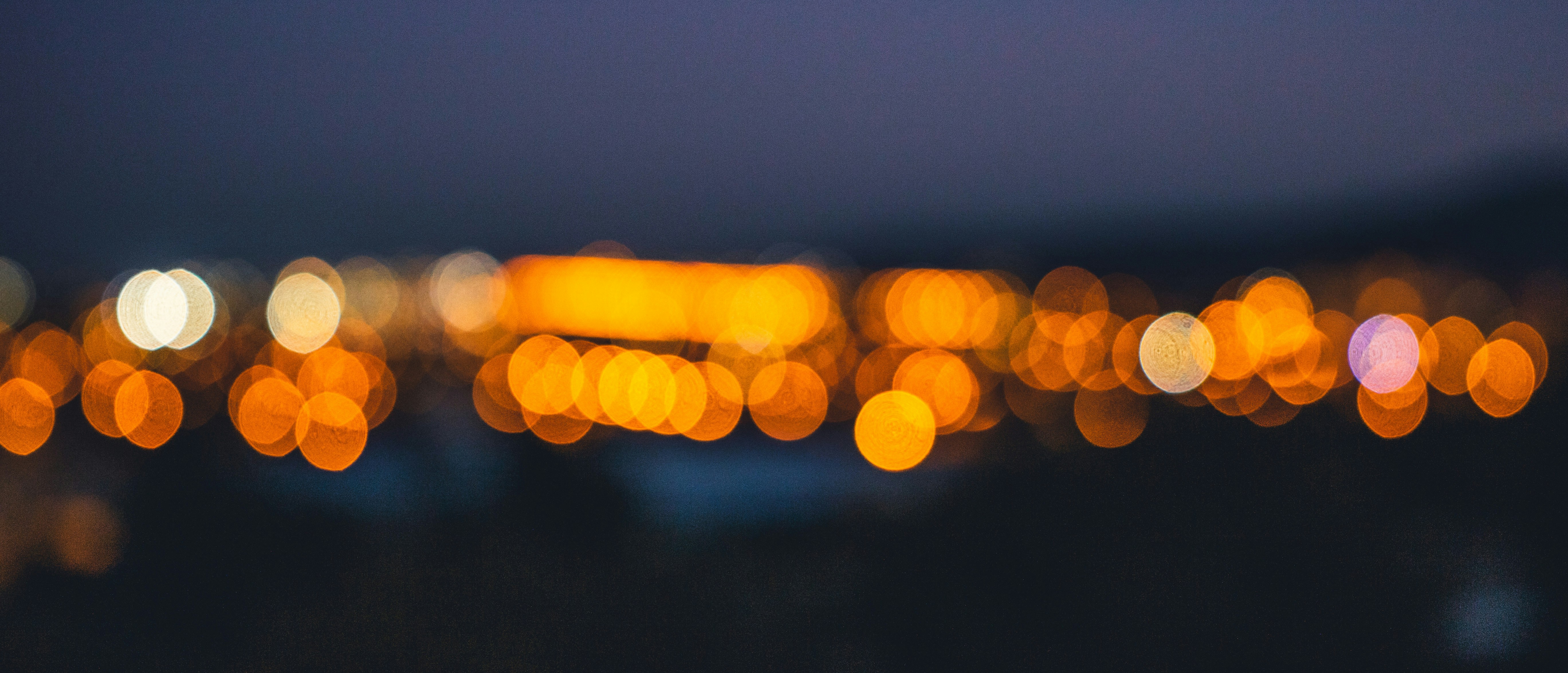 Blurred city background with night lights and warm tones and gorgeous bokeh. | a blurry photo of a city at night