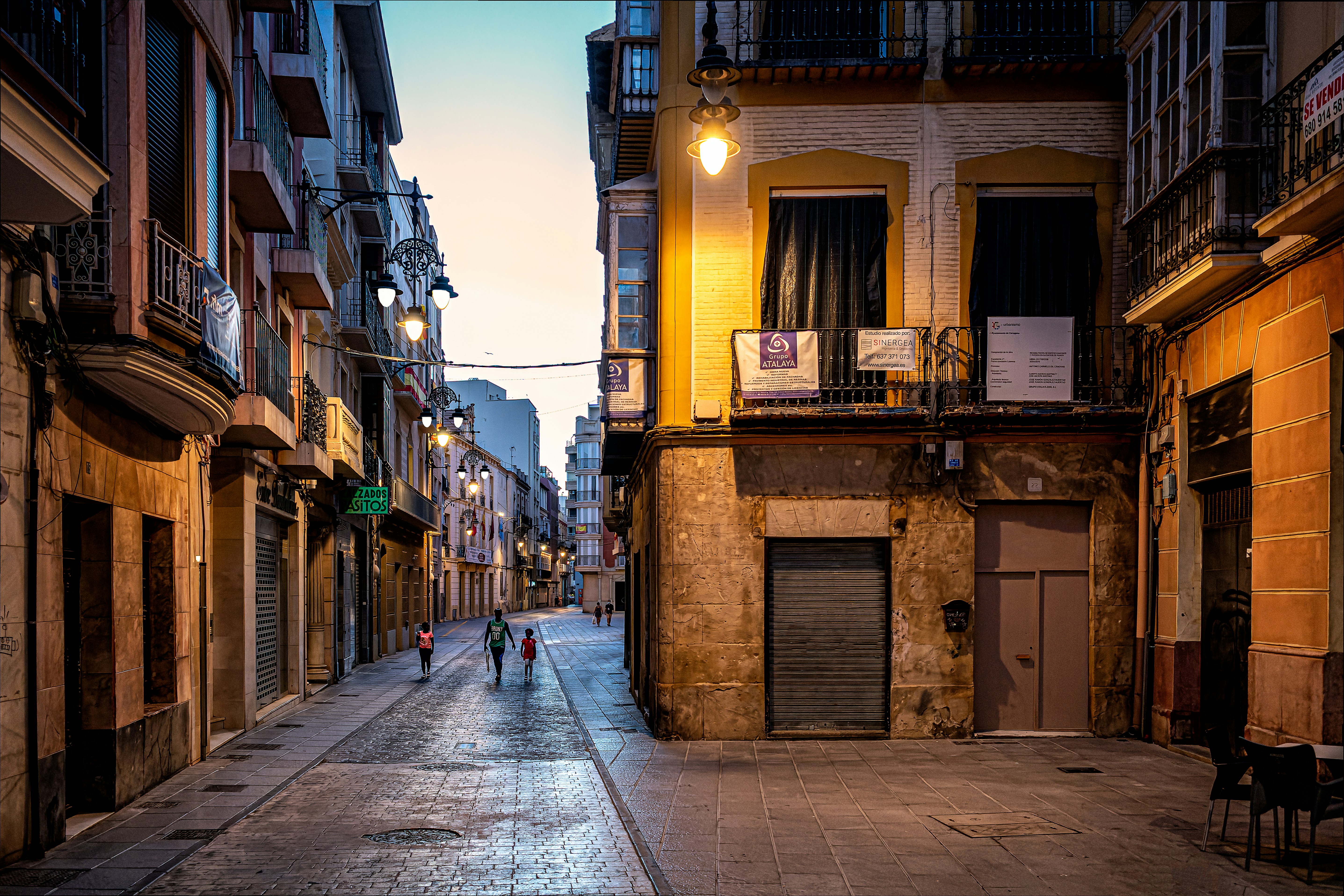 Quiet cobblestone street in Cartagena at dusk, with warm lights illuminating historic buildings.