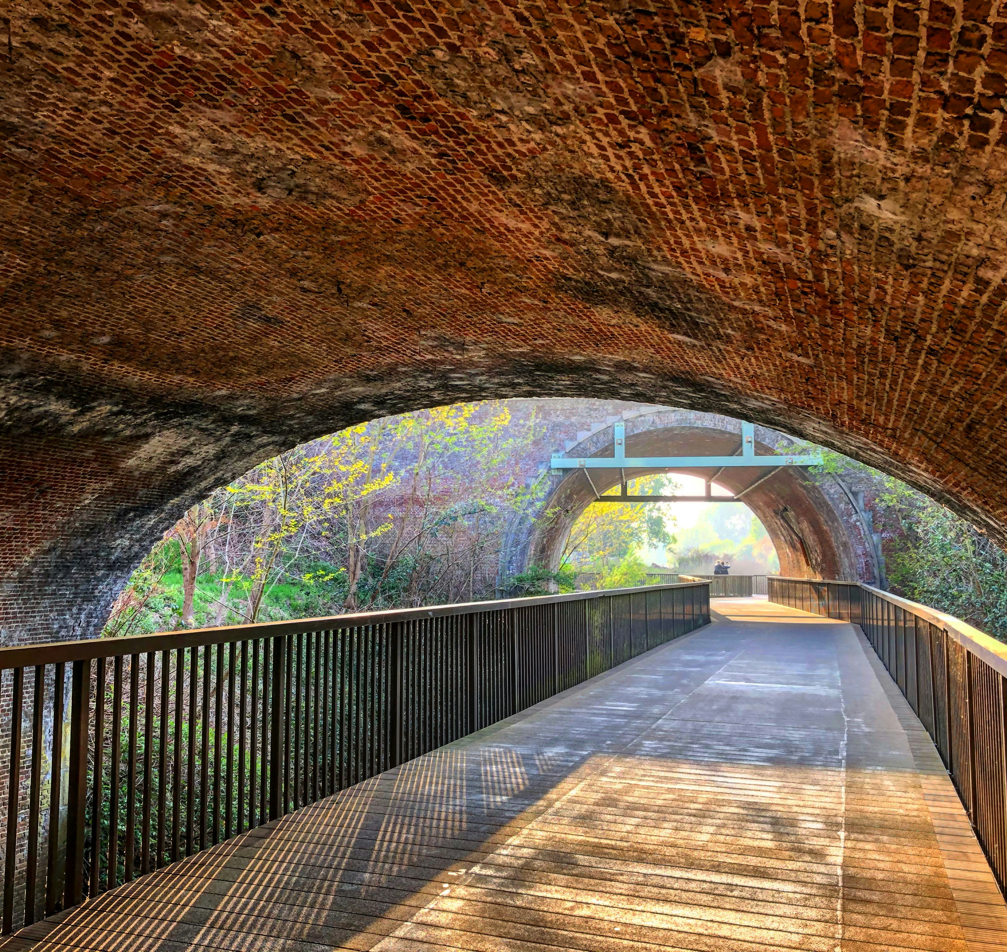 A walkway under a bridge with a light at the end photo – Free Belgium ...