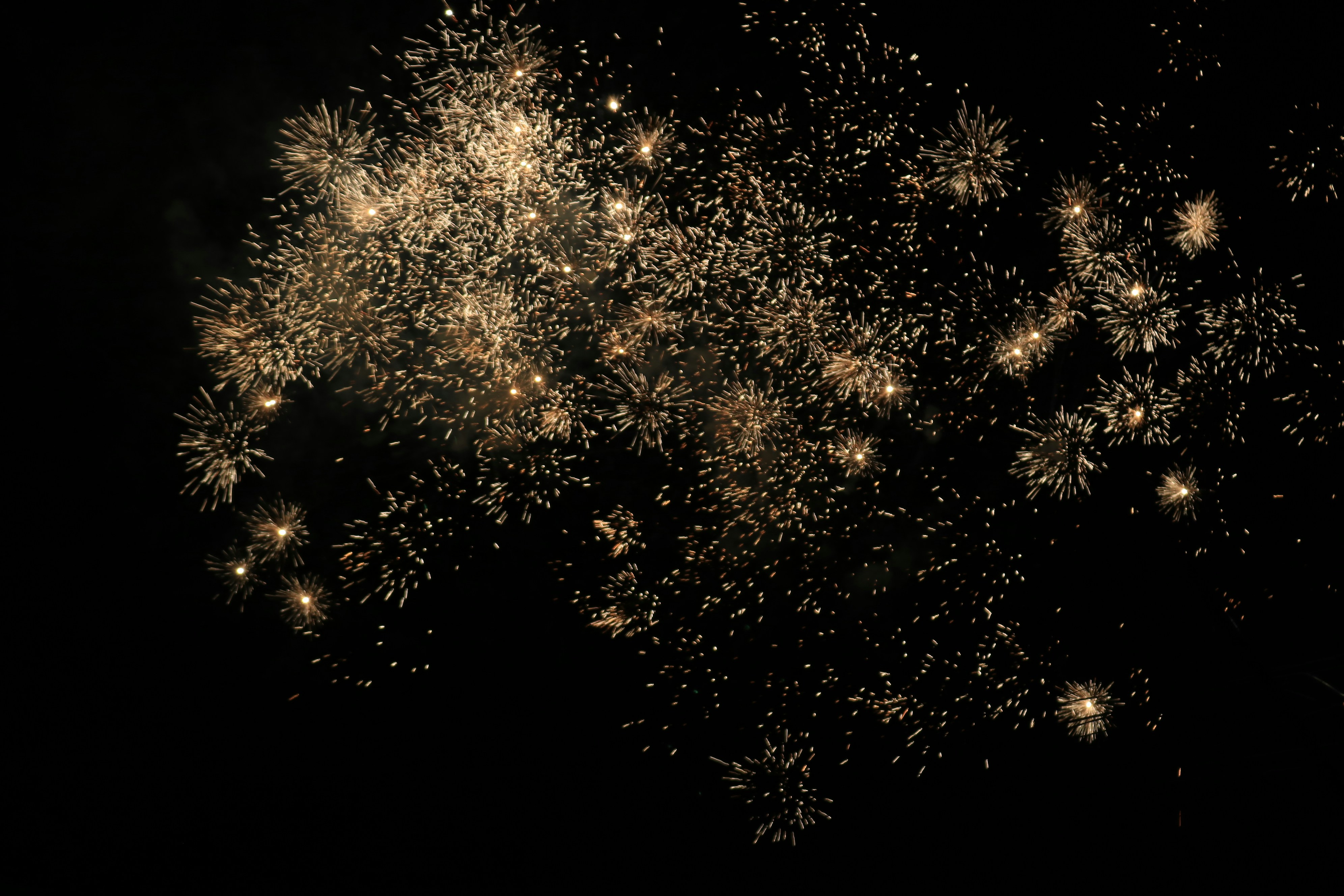 Golden fireworks burst against a dark sky, creating a dazzling display of light and sparkles.