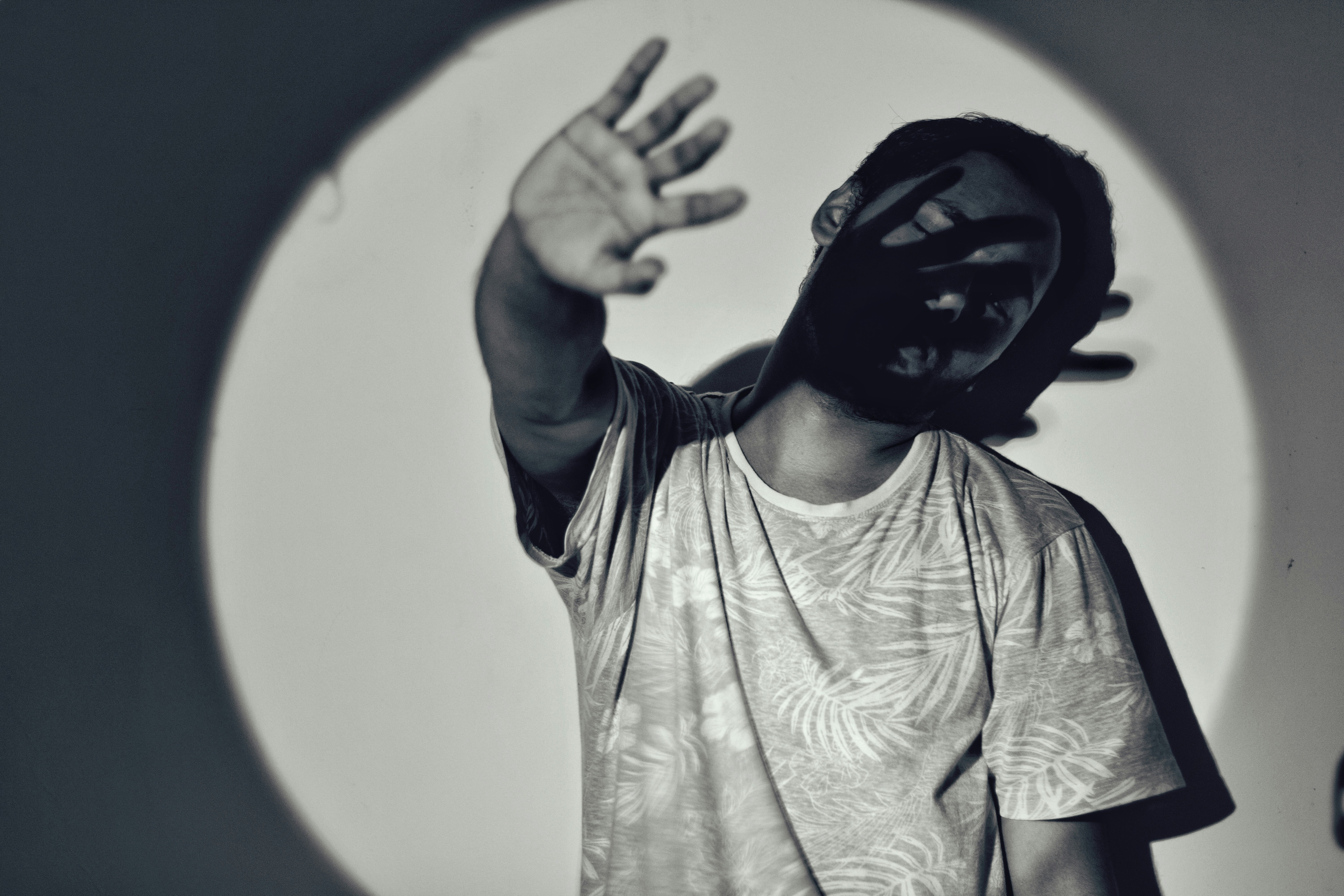 A figure obscured by shadows raises a hand against a bright circular backdrop, evoking themes of struggle and defiance.