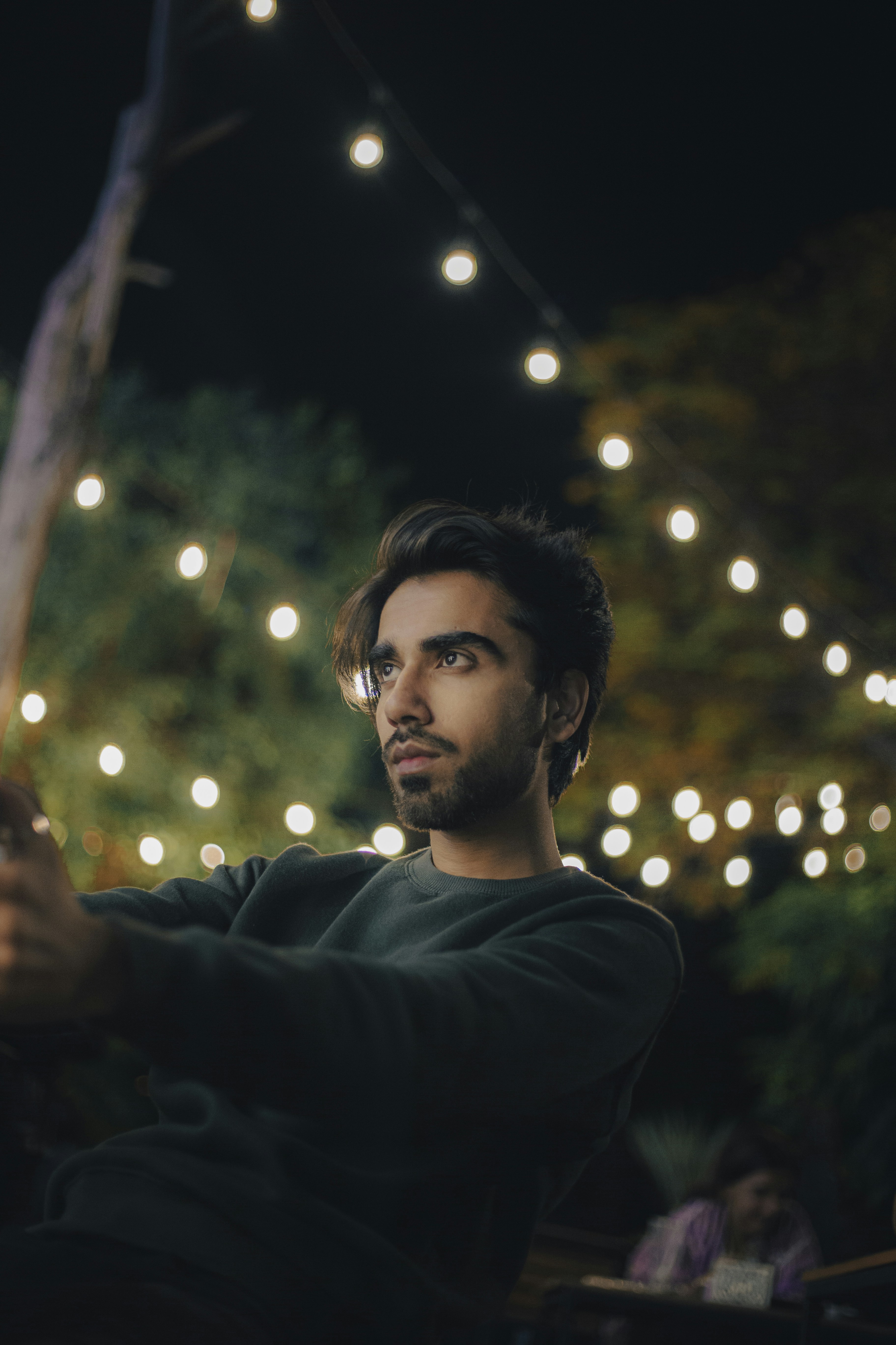 A man sitting in front of a string of lights photo – Free Person Image ...