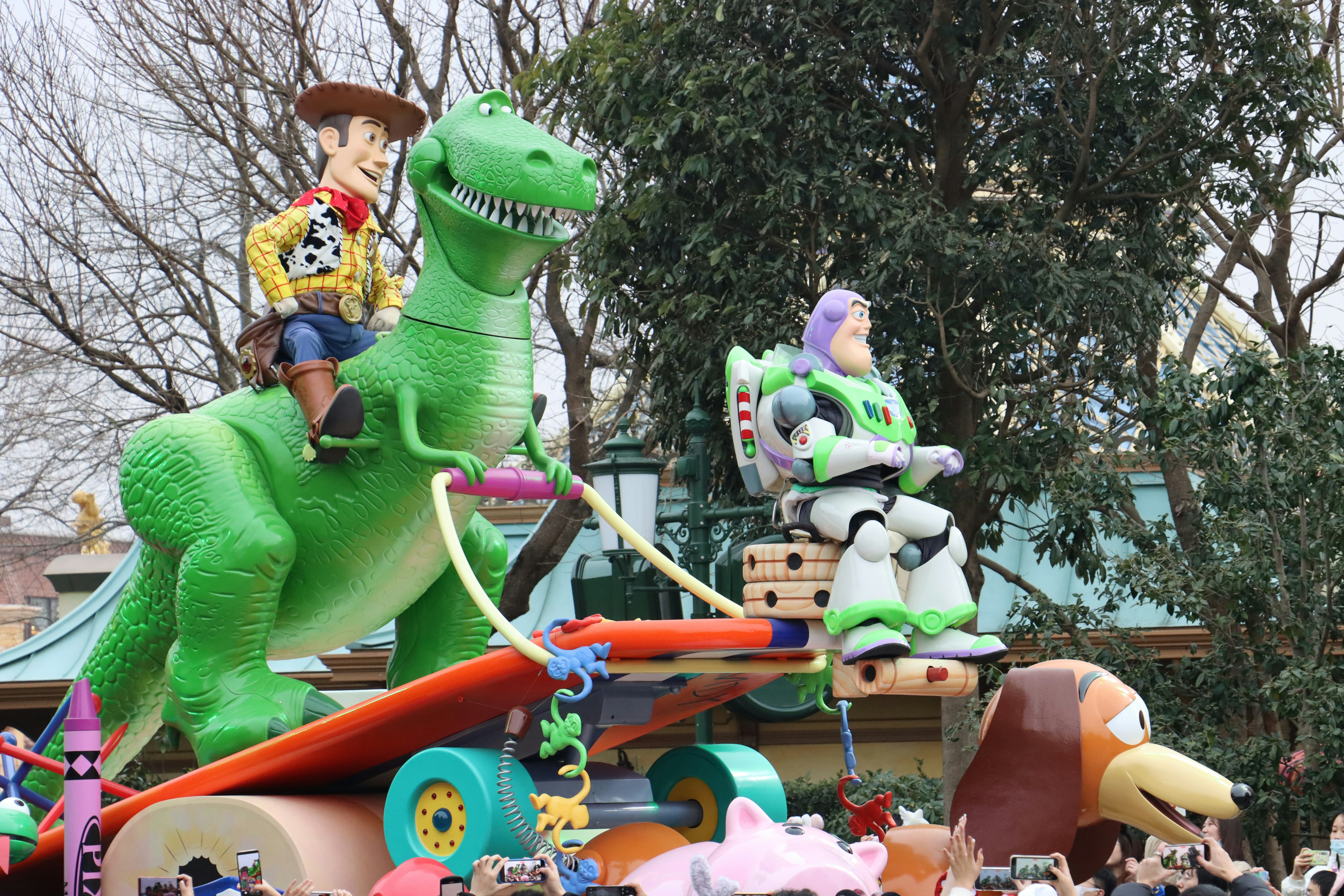 A parade float featuring toy story characters riding a dinosaur photo ...