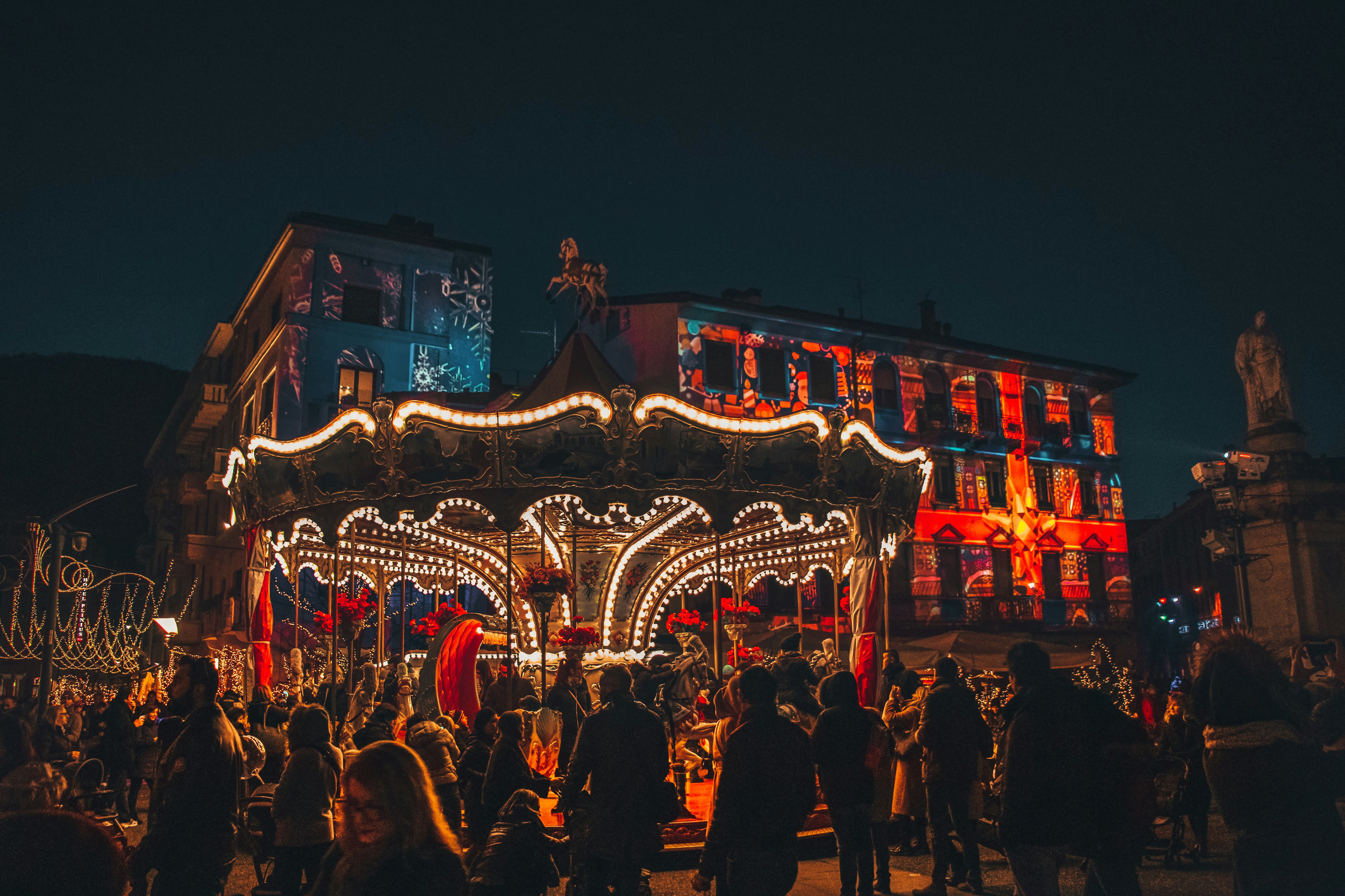 A crowd of people standing around a merry go round photo – Free Human ...