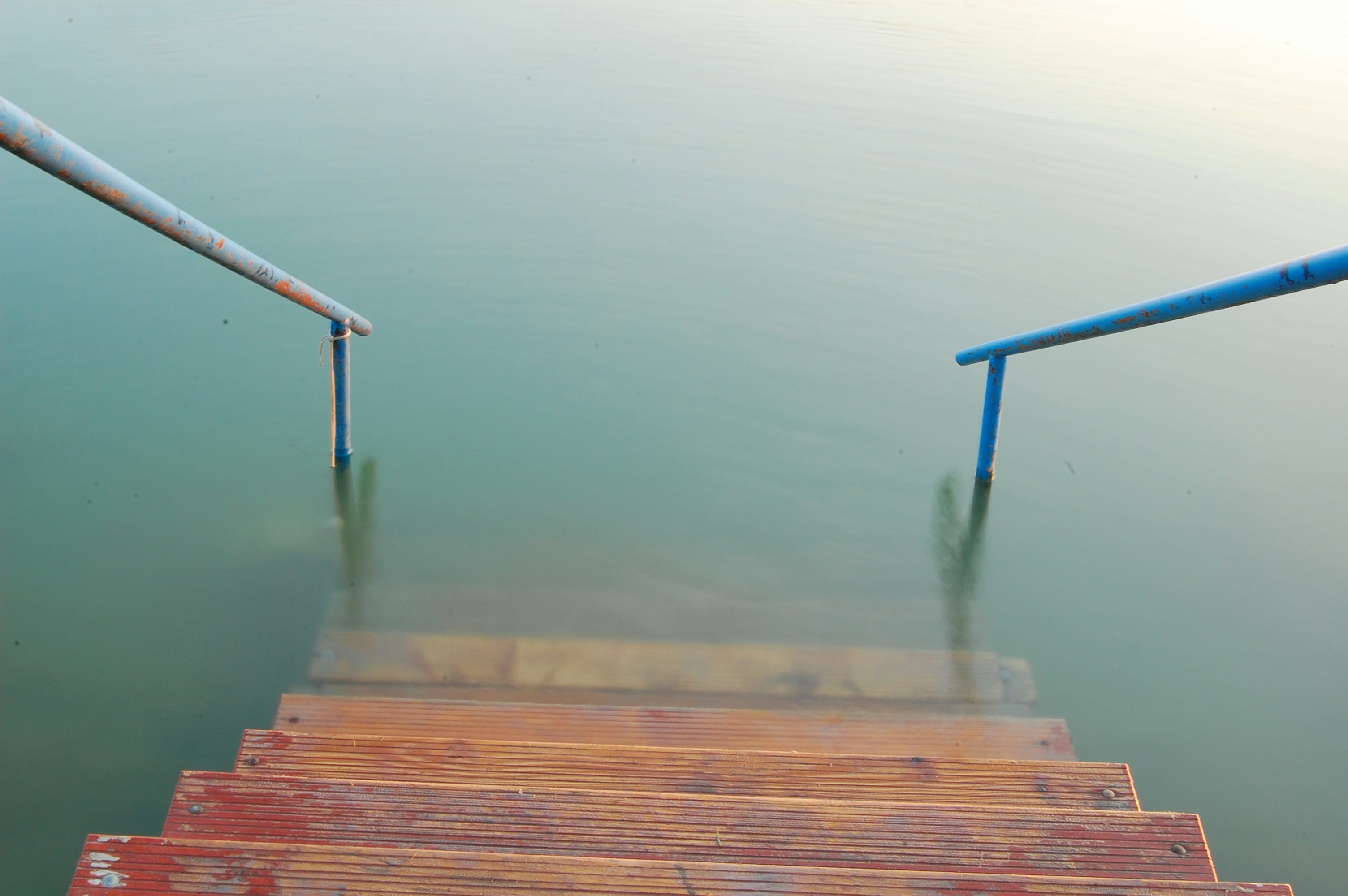 Quiet Descent: A Rusted Staircase into Tranquil Teal Waters