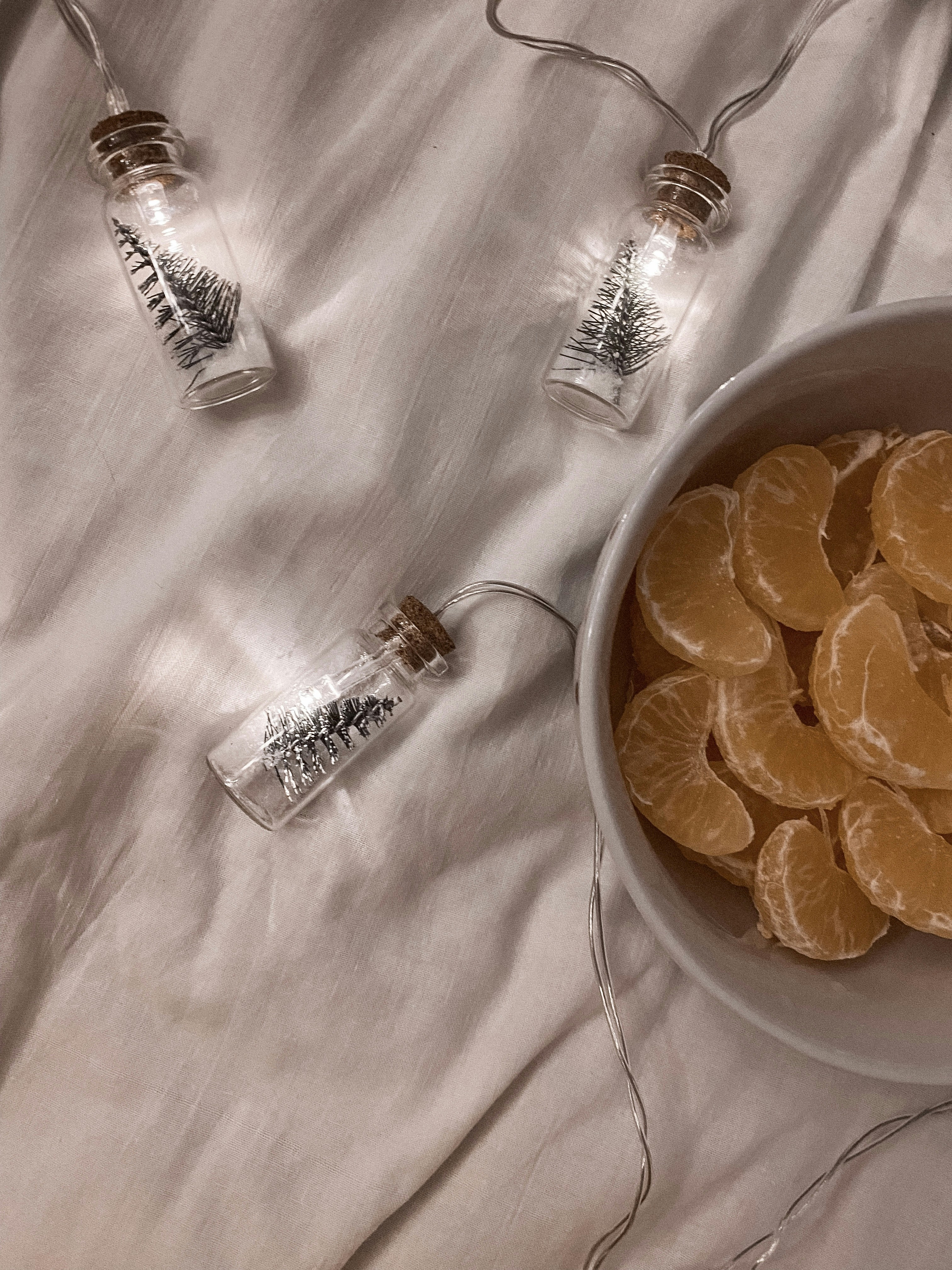 Luminous Linen Still-Life: Bottle Lights Framing a Bowl of Orange Slices