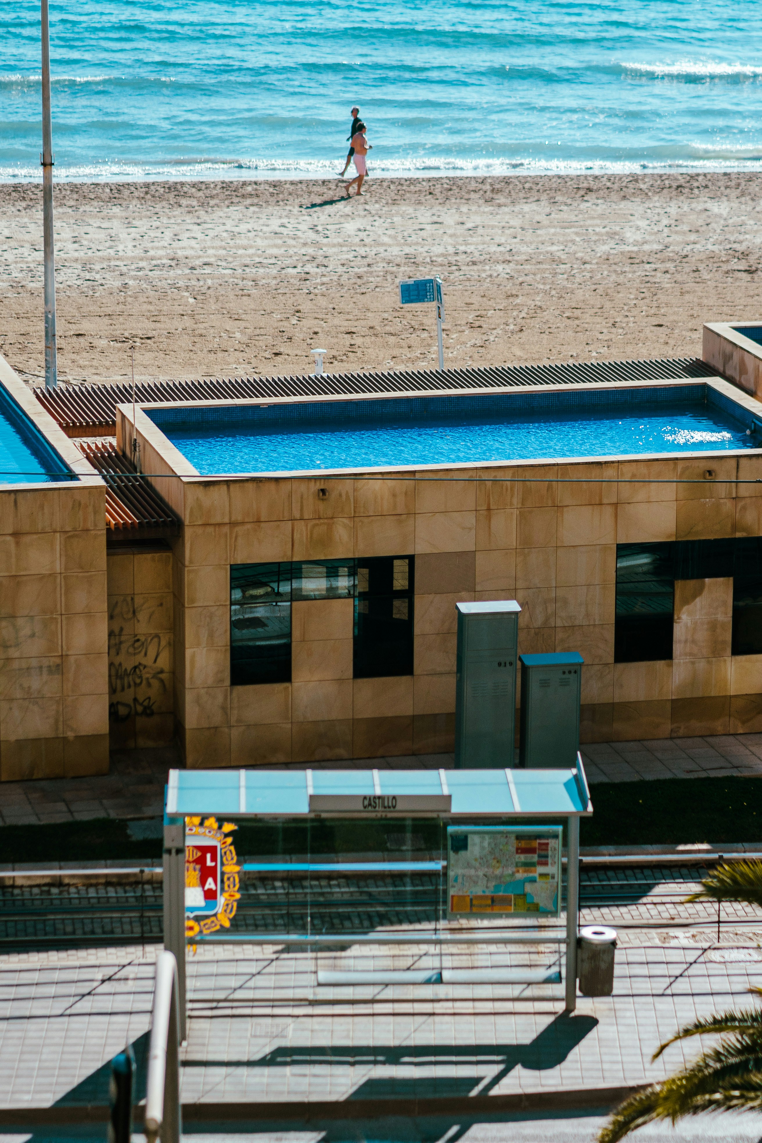 a person walking on a beach next to a swimming pool