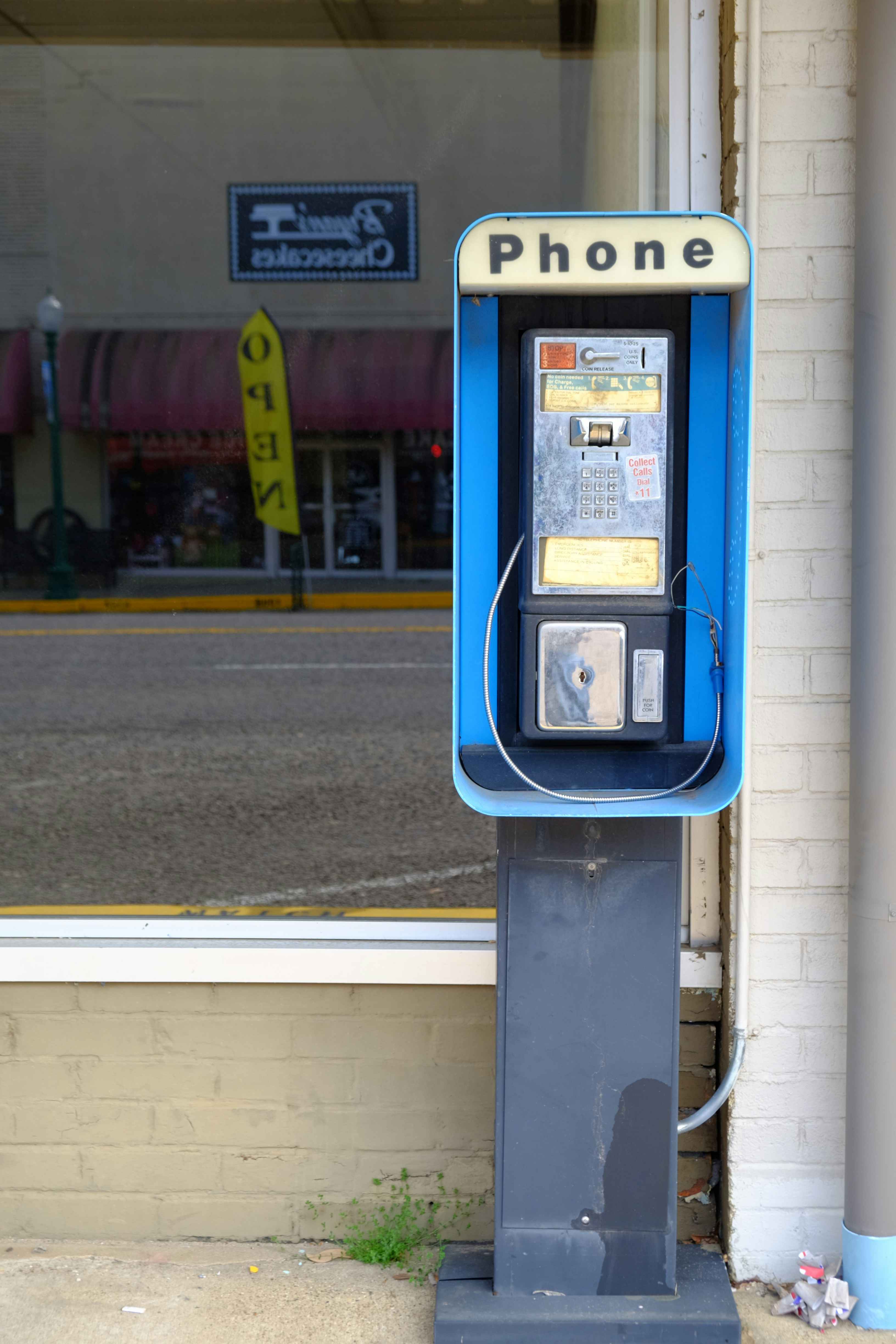 A blue pay phone sitting next to a building photo – Free Machine Image ...