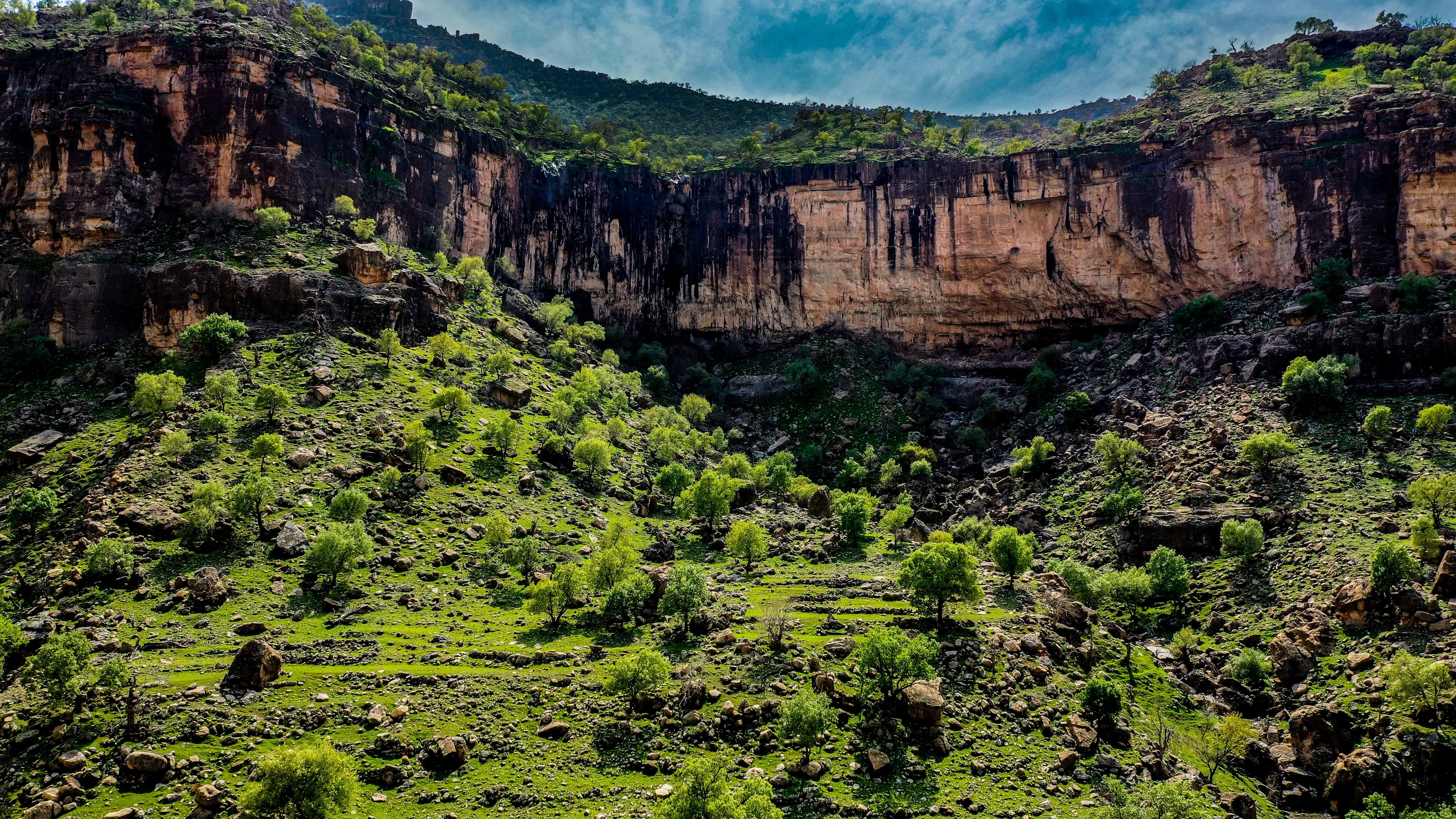 Lush green vegetation clings to a rocky escarpment under a vibrant blue sky.
