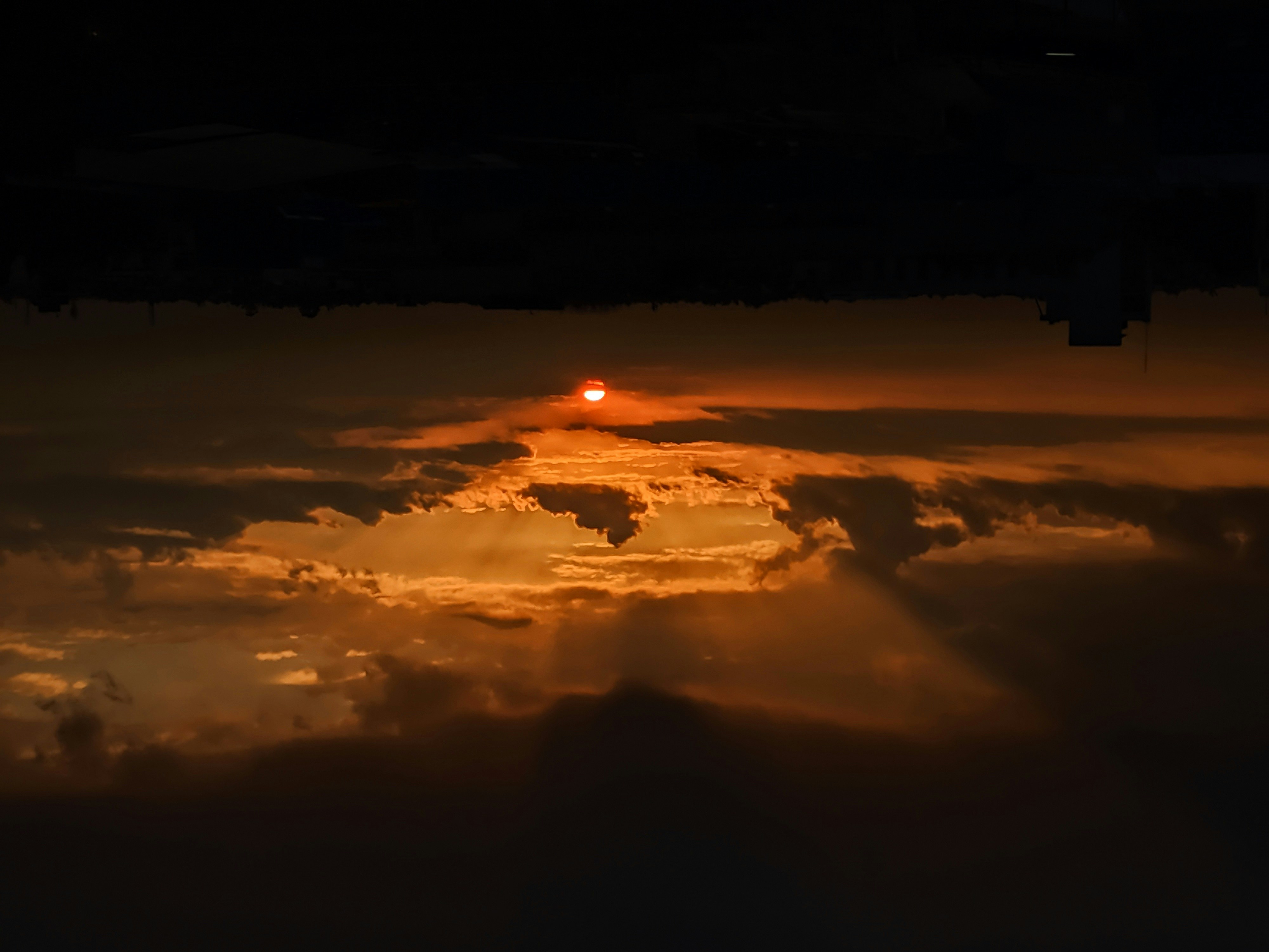 Vibrant sunset casting warm hues over a dramatic cloud formation, highlighting the interplay of light and shadow.