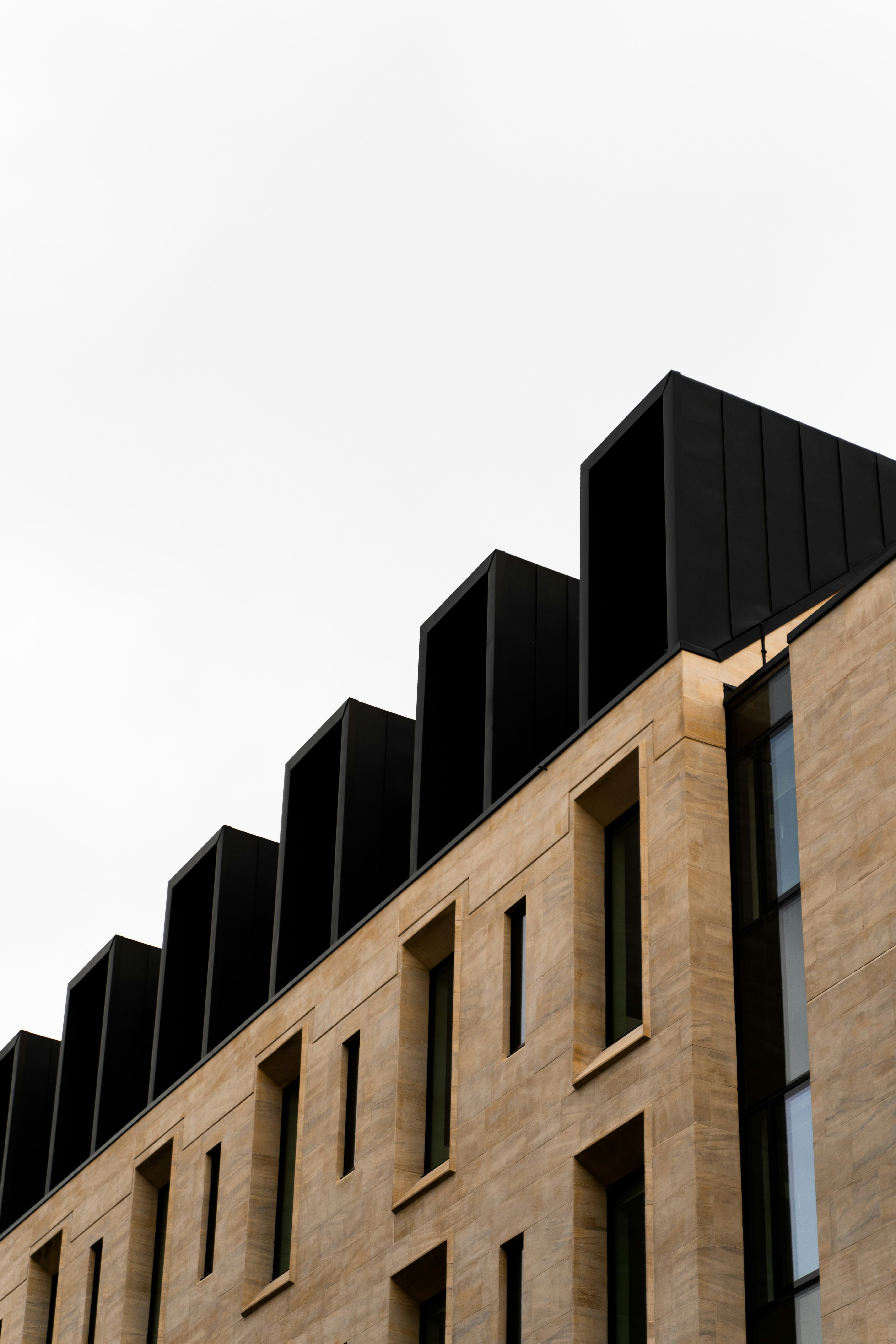 Contemporary building showcasing a blend of textured stone and sleek black elements, emphasizing geometric design and urban aesthetics.