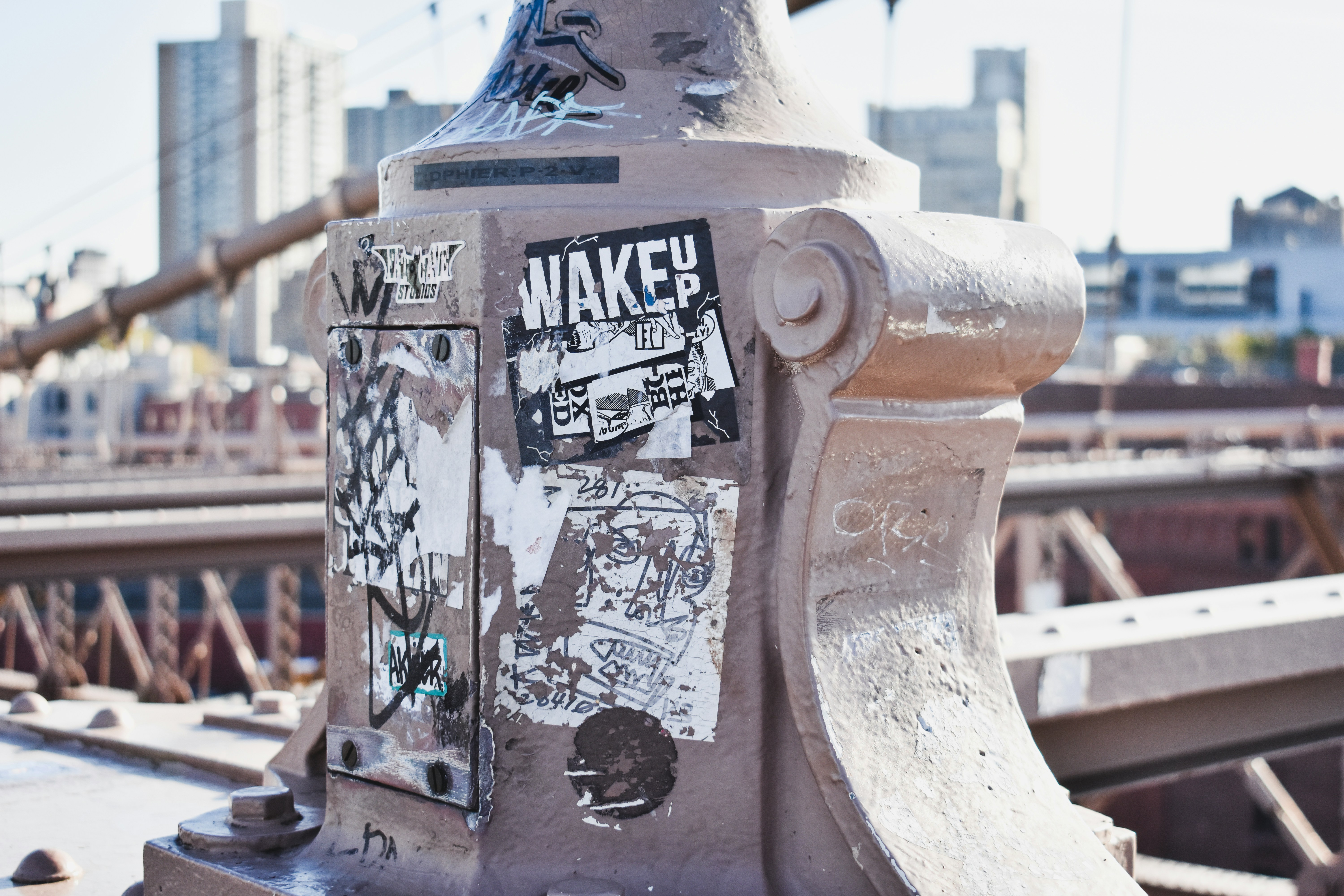 Stickered urban lamppost on a distant bridge