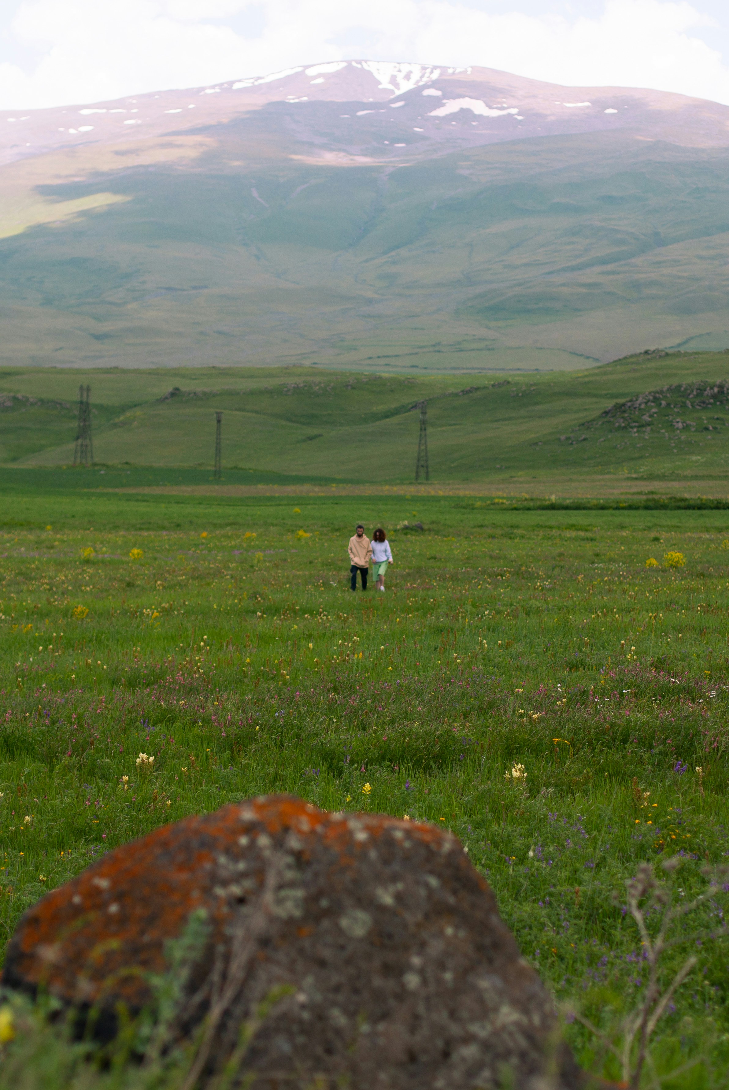 steady walk | two people standing in a field with a mountain in the background