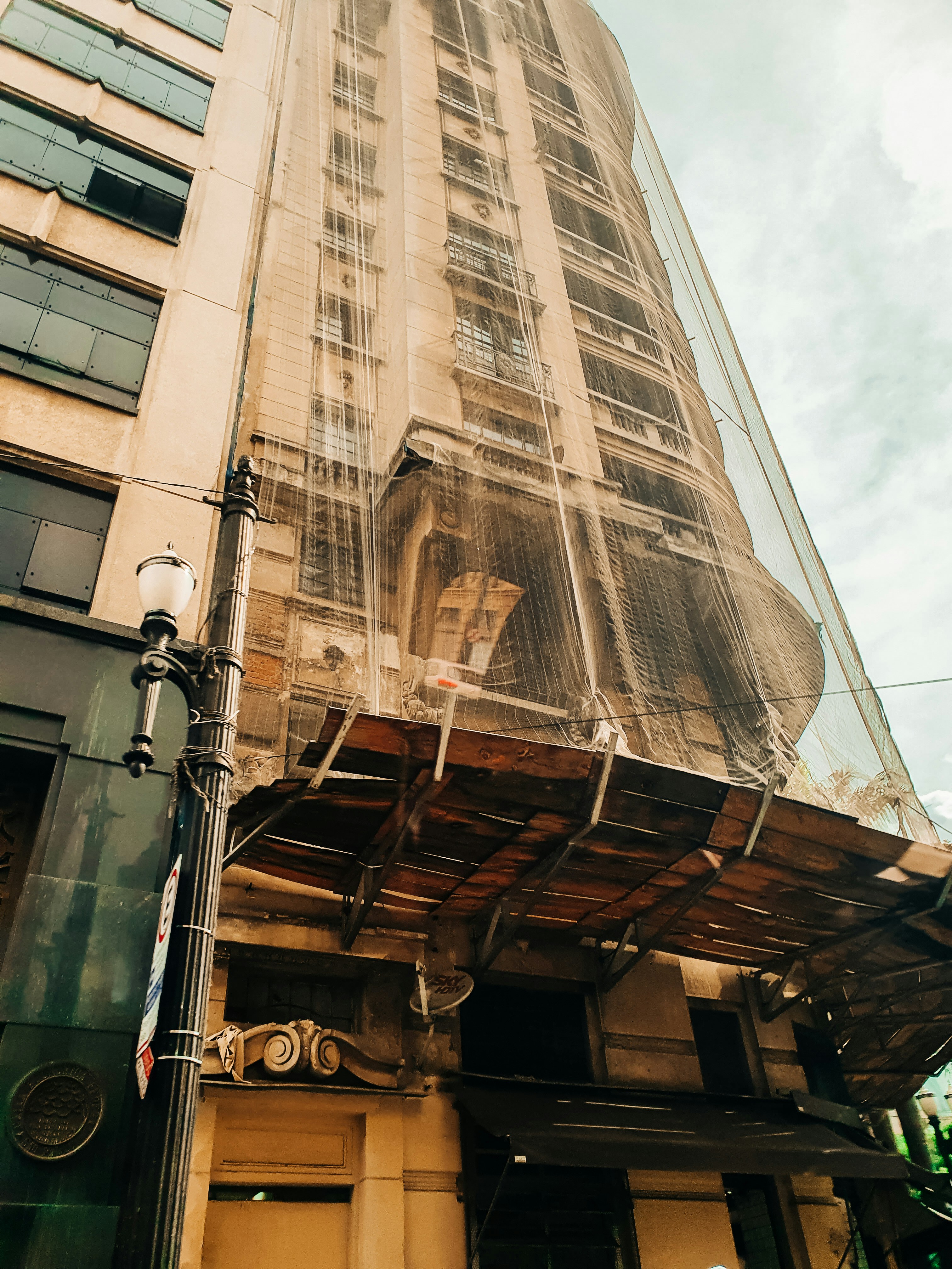 Historic building under renovation, partially obscured by protective netting, showcasing intricate architectural details.