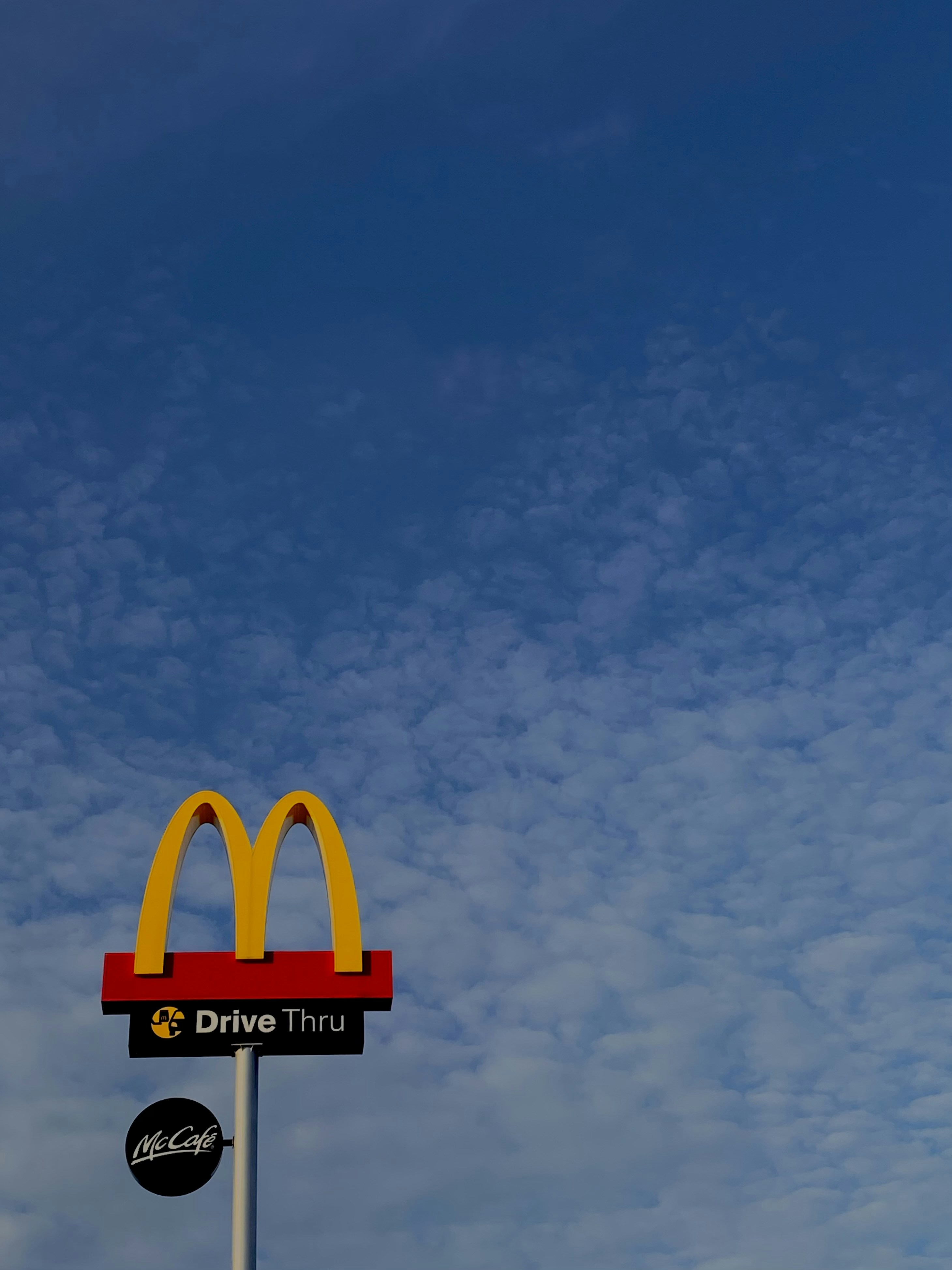 A mcdonald's drive thru sign in front of a cloudy blue sky photo – Free ...