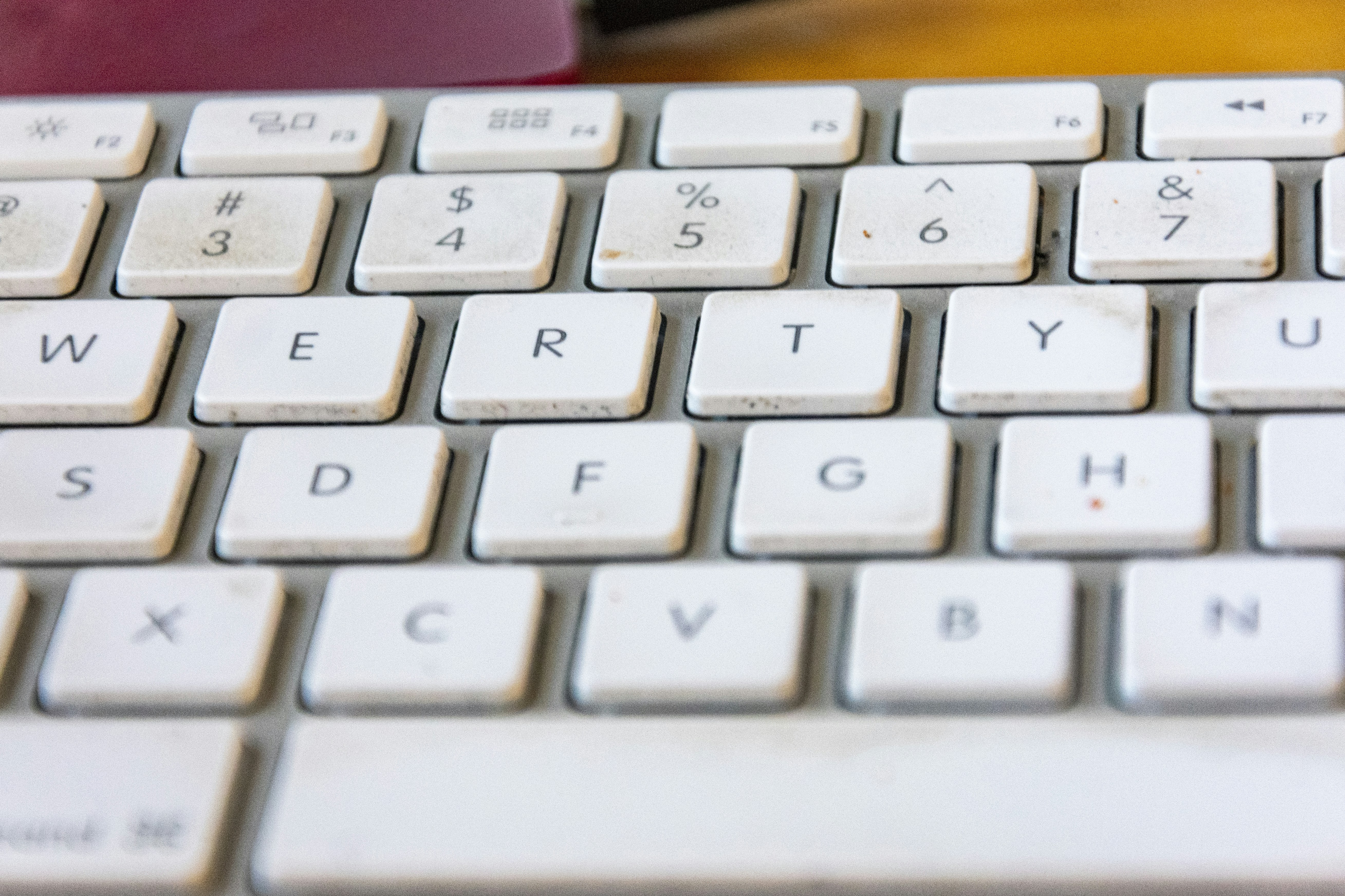 Close-up view of a computer keyboard, showcasing worn keys and a vibrant background. Perfect for illustrating the nuances of daily digital interaction.