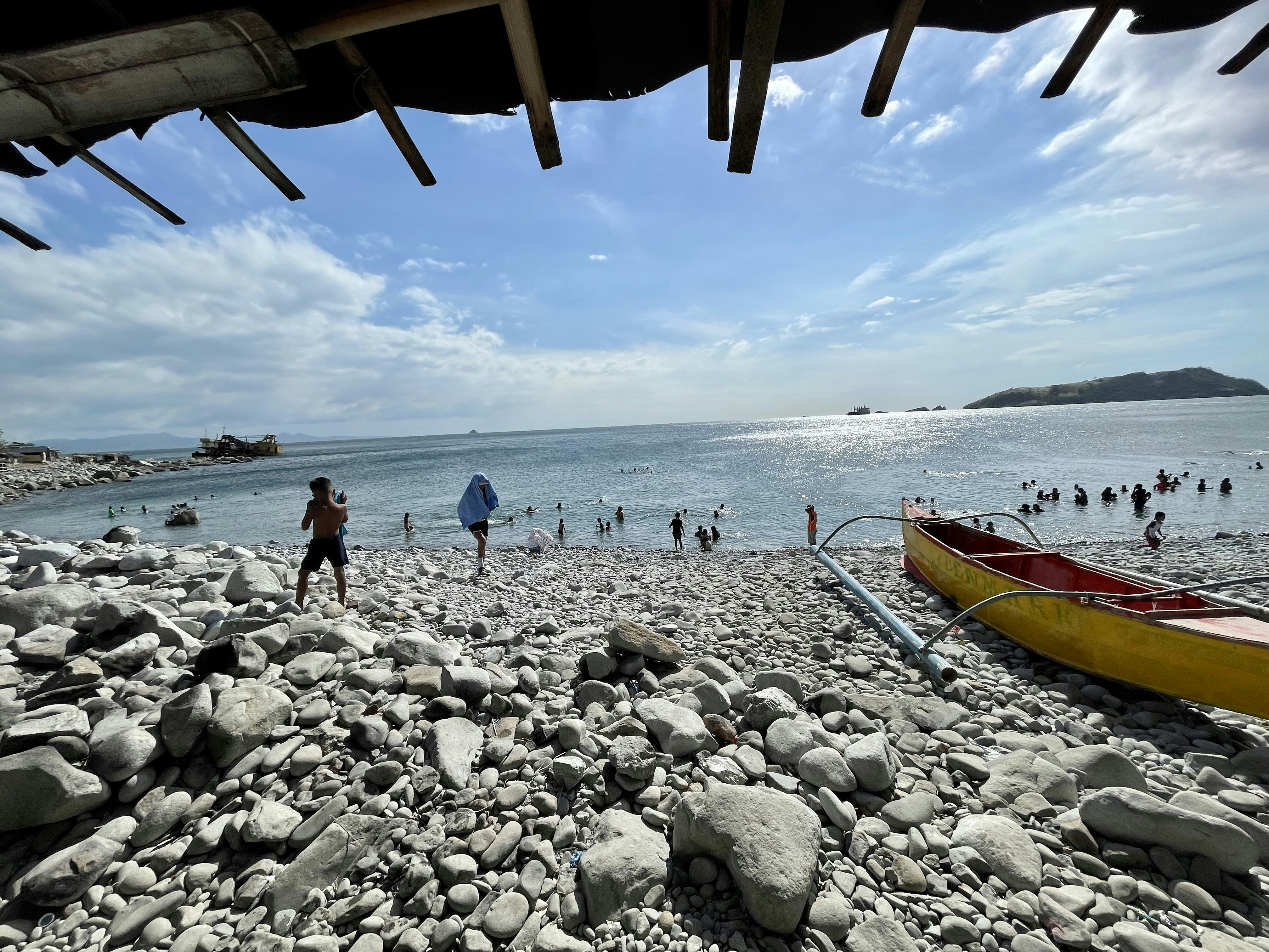 A group of people standing on top of a beach next to a body of water ...