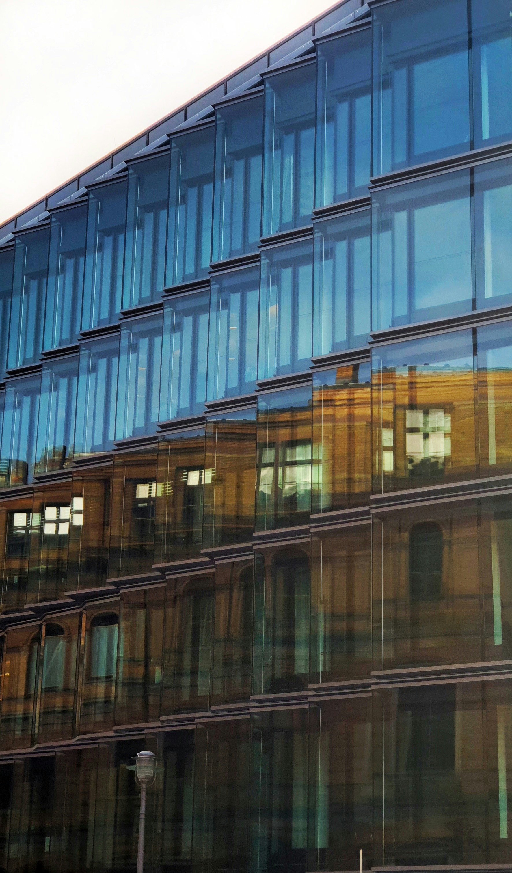 Modern glass building reflecting the historic architecture of its surroundings, showcasing a blend of old and new design elements.