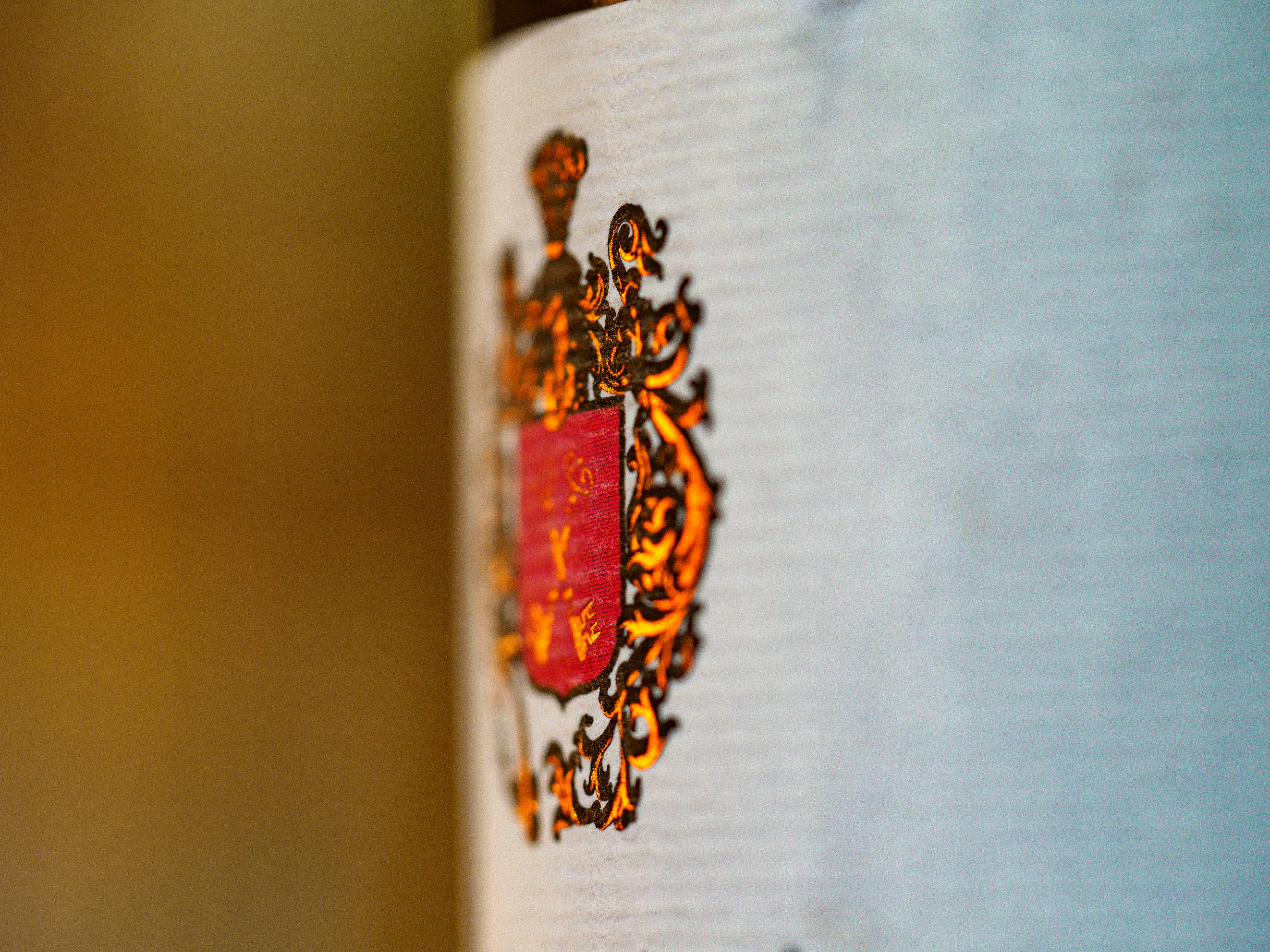 Intricate coat of arms embossed on a textured wine label, showcasing rich colors and detailed craftsmanship.