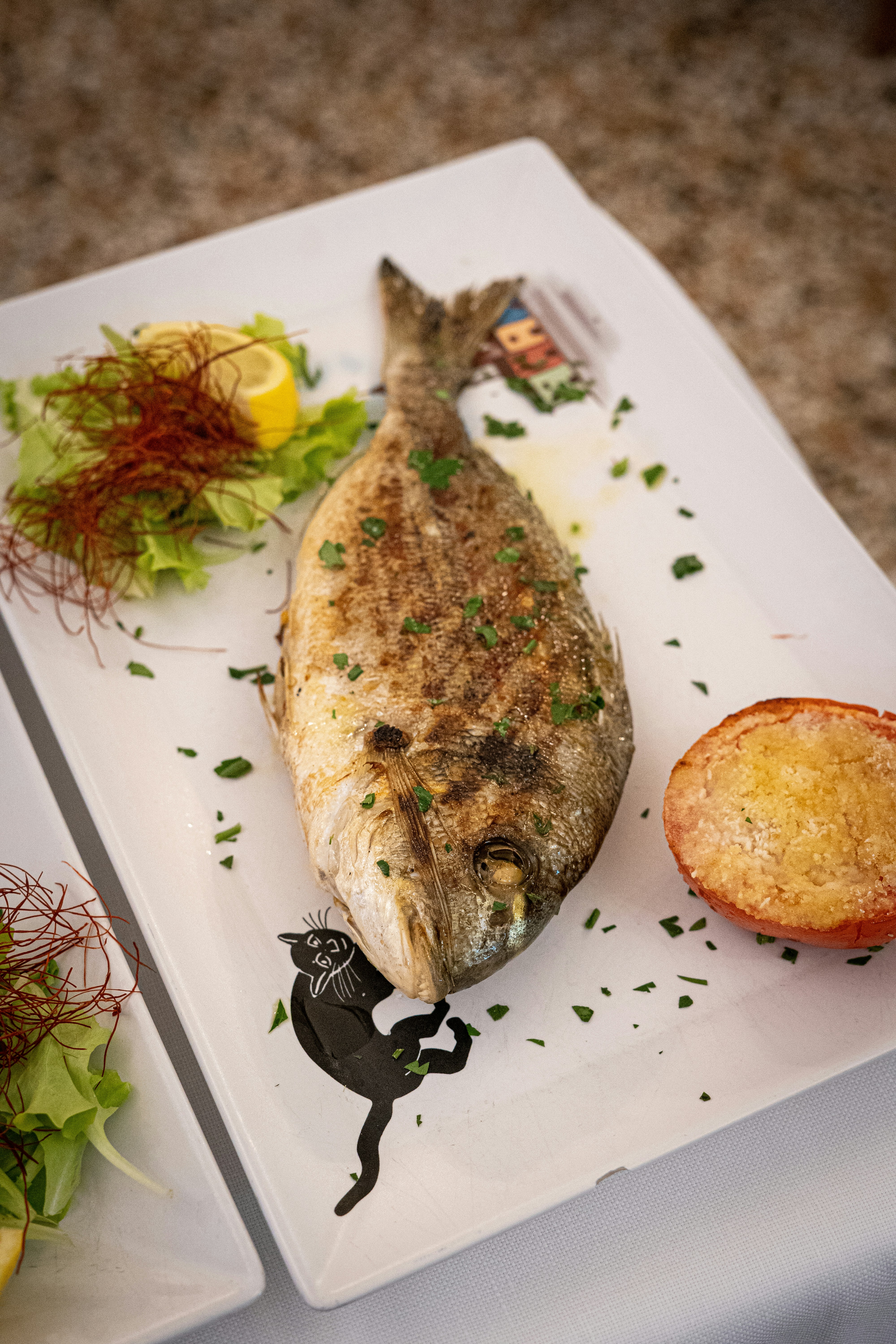 A white plate topped with a fish next to a piece of bread photo – Free ...
